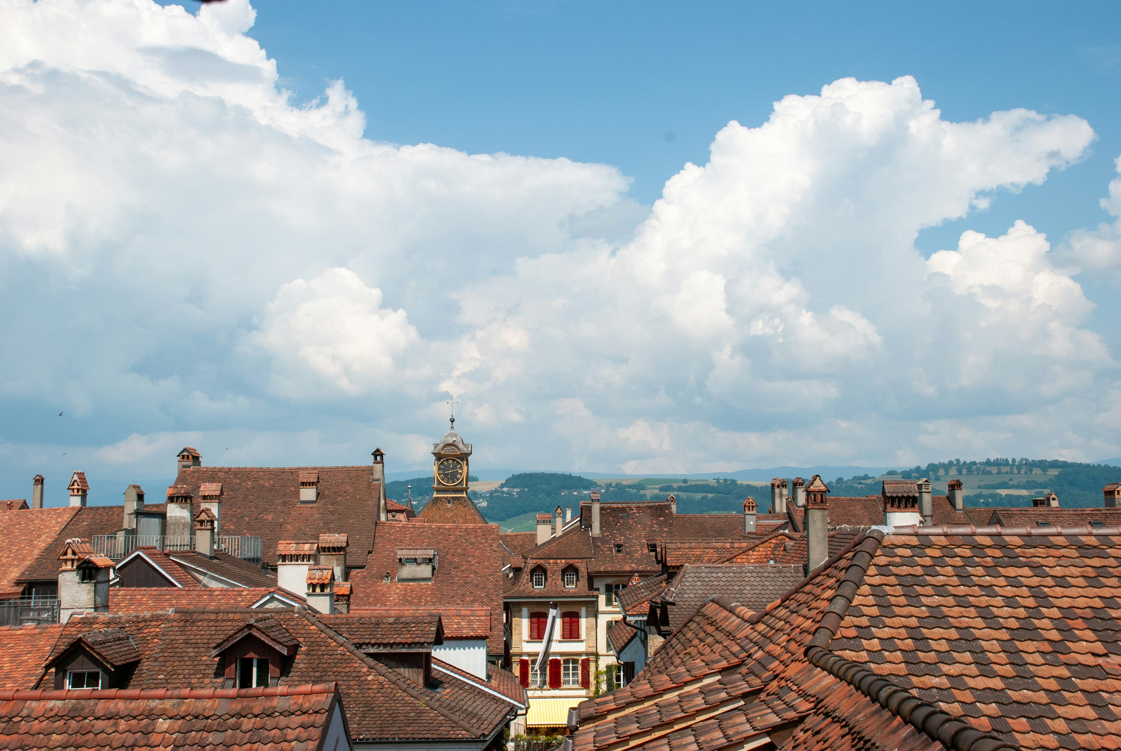 Clock Tower Amid Red Rooftops Beneath a Cloud-Scattered Sky