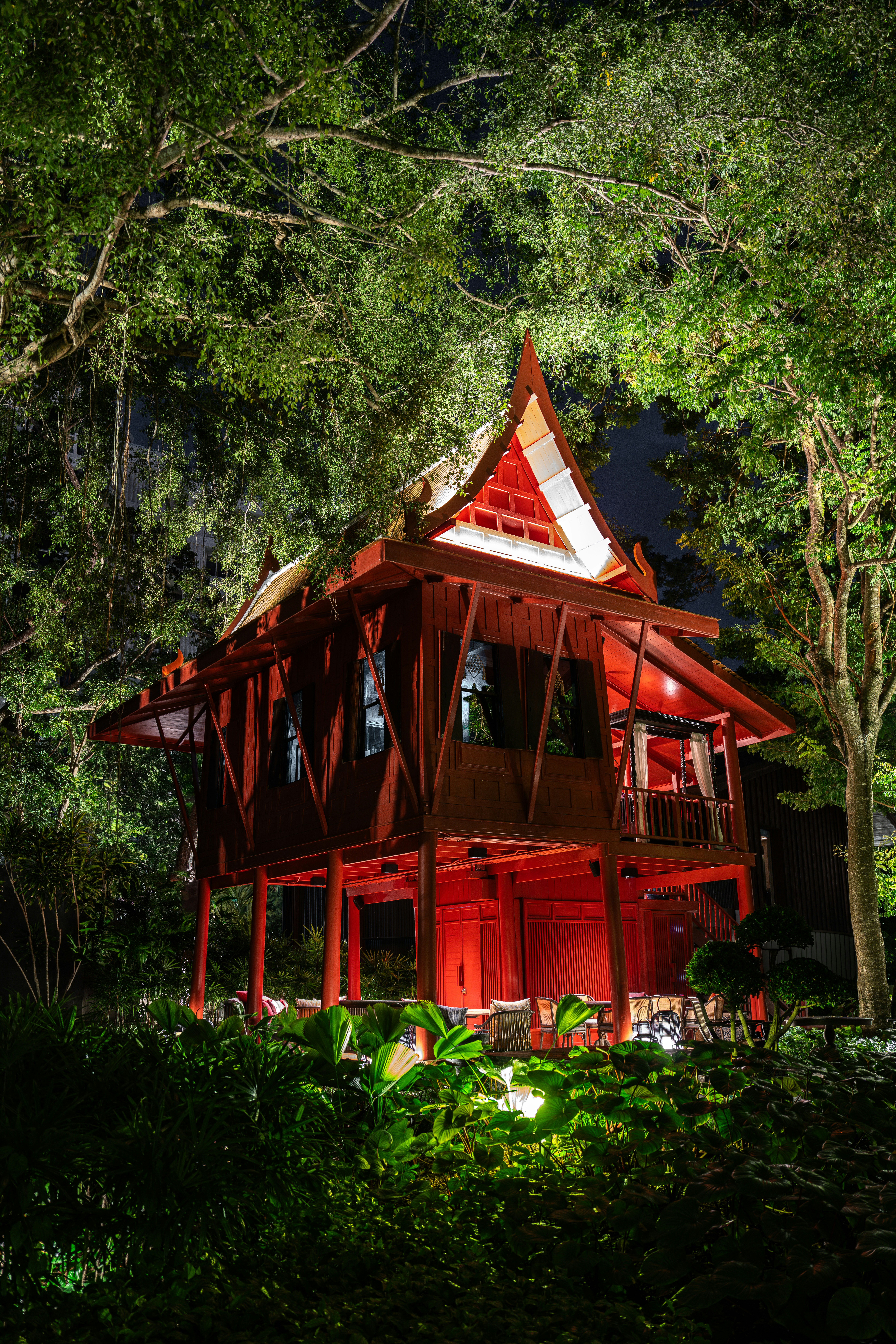 Red Timber Pavilion Rising from Night Foliage