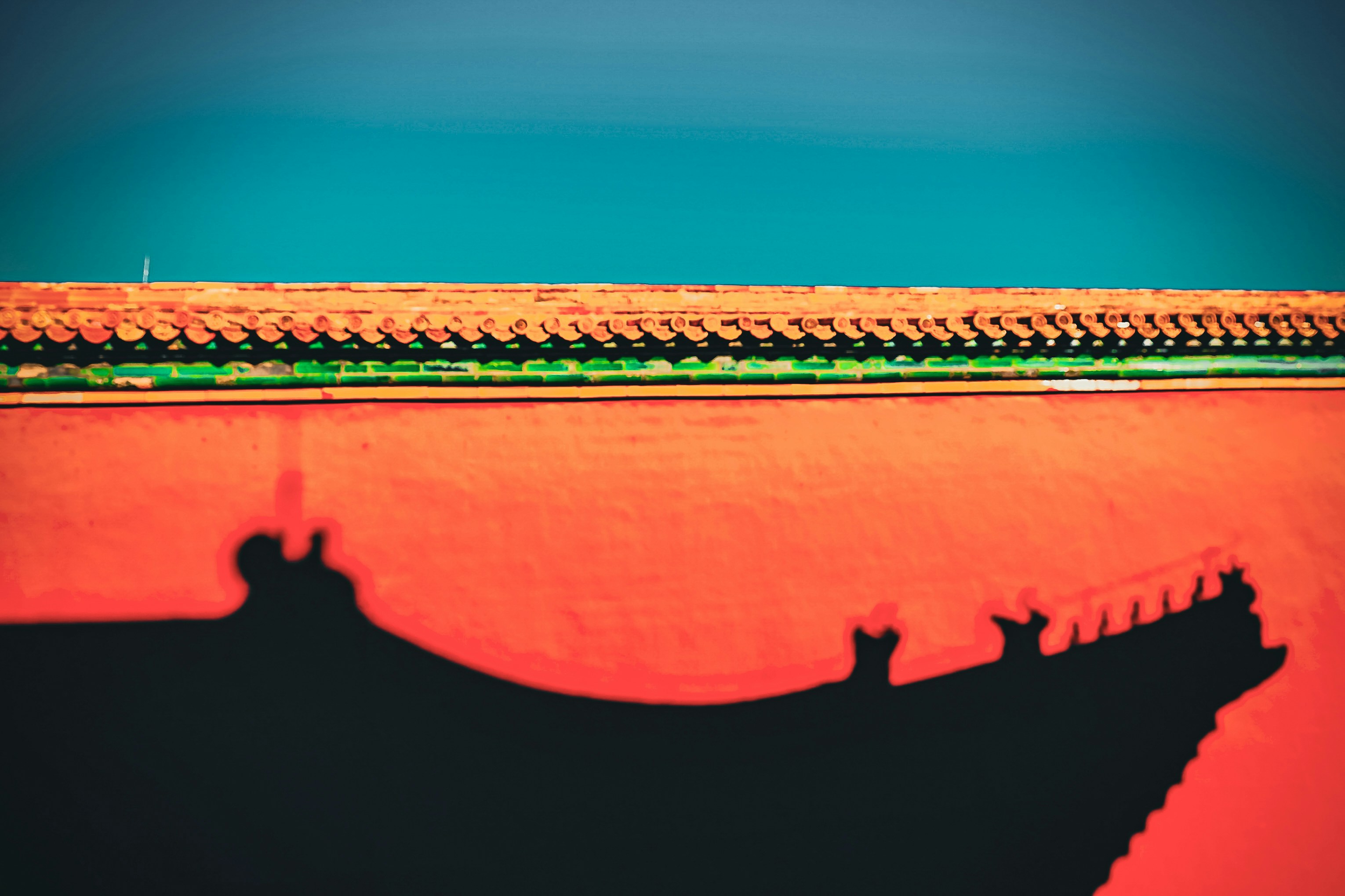 Crimson Wall, Teal Sky: Rooftop Shadowplay