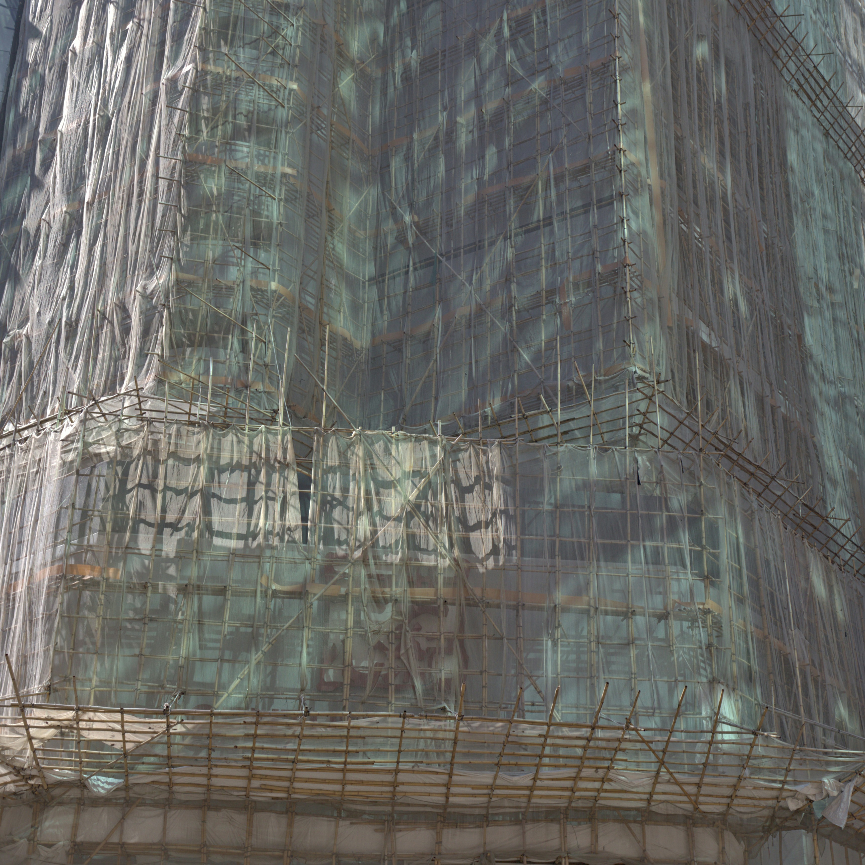 Grid-Wrapped Glass Tower: Construction Veil on a Modern Facade