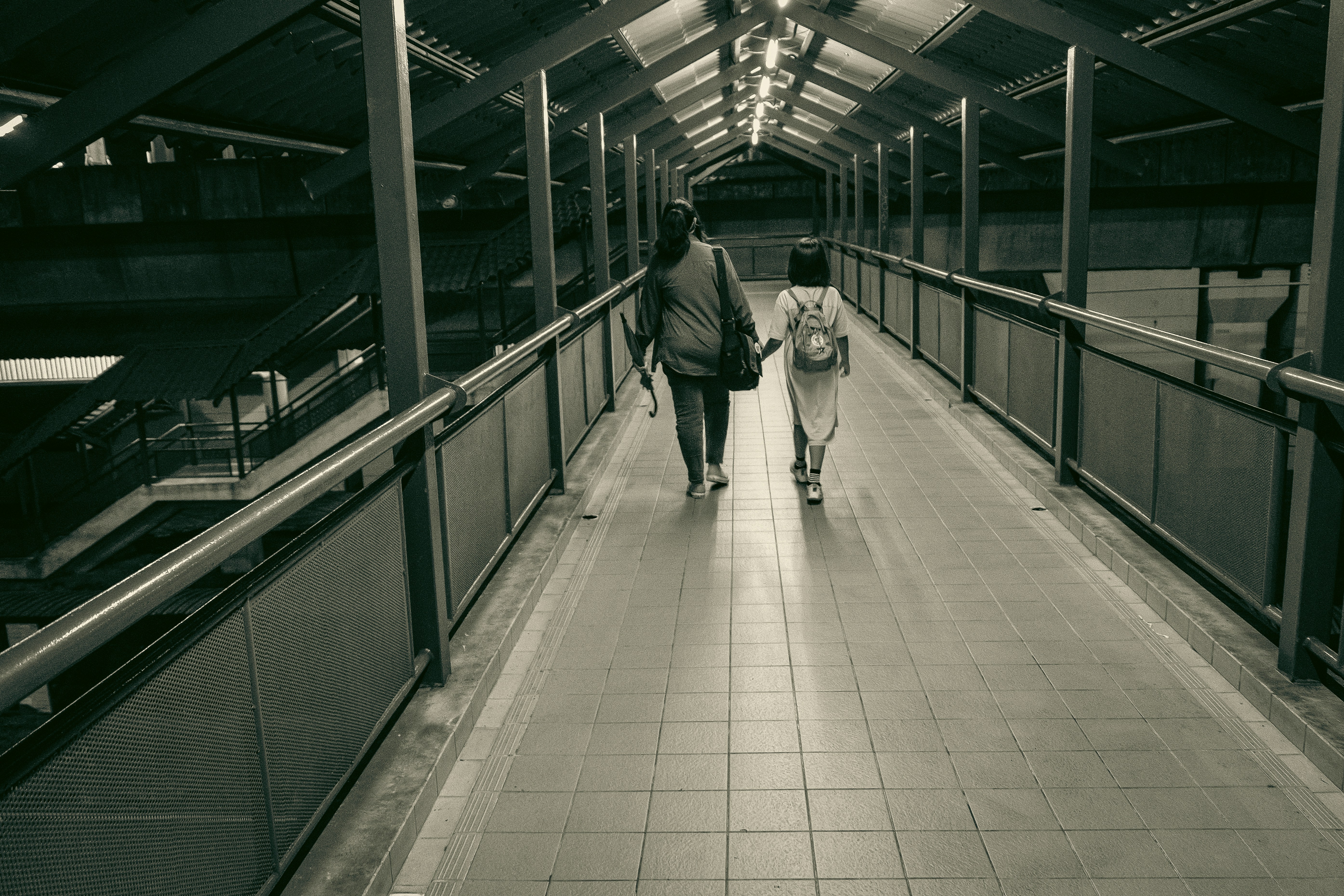 Monochrome Vanishing Point: Two Figures on a Symmetrical Walkway