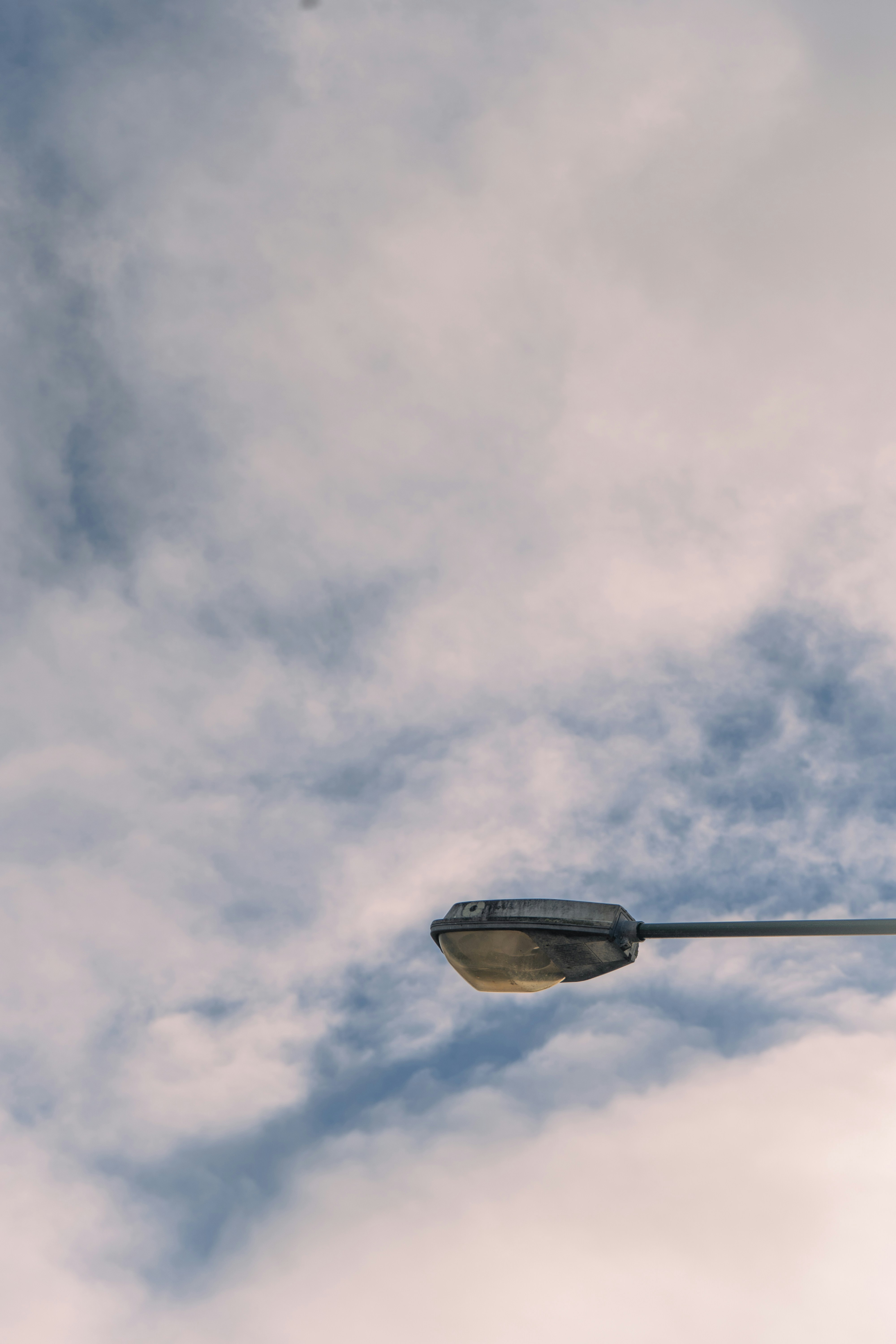 Skyline Sentinel: A lone streetlamp through wispy clouds