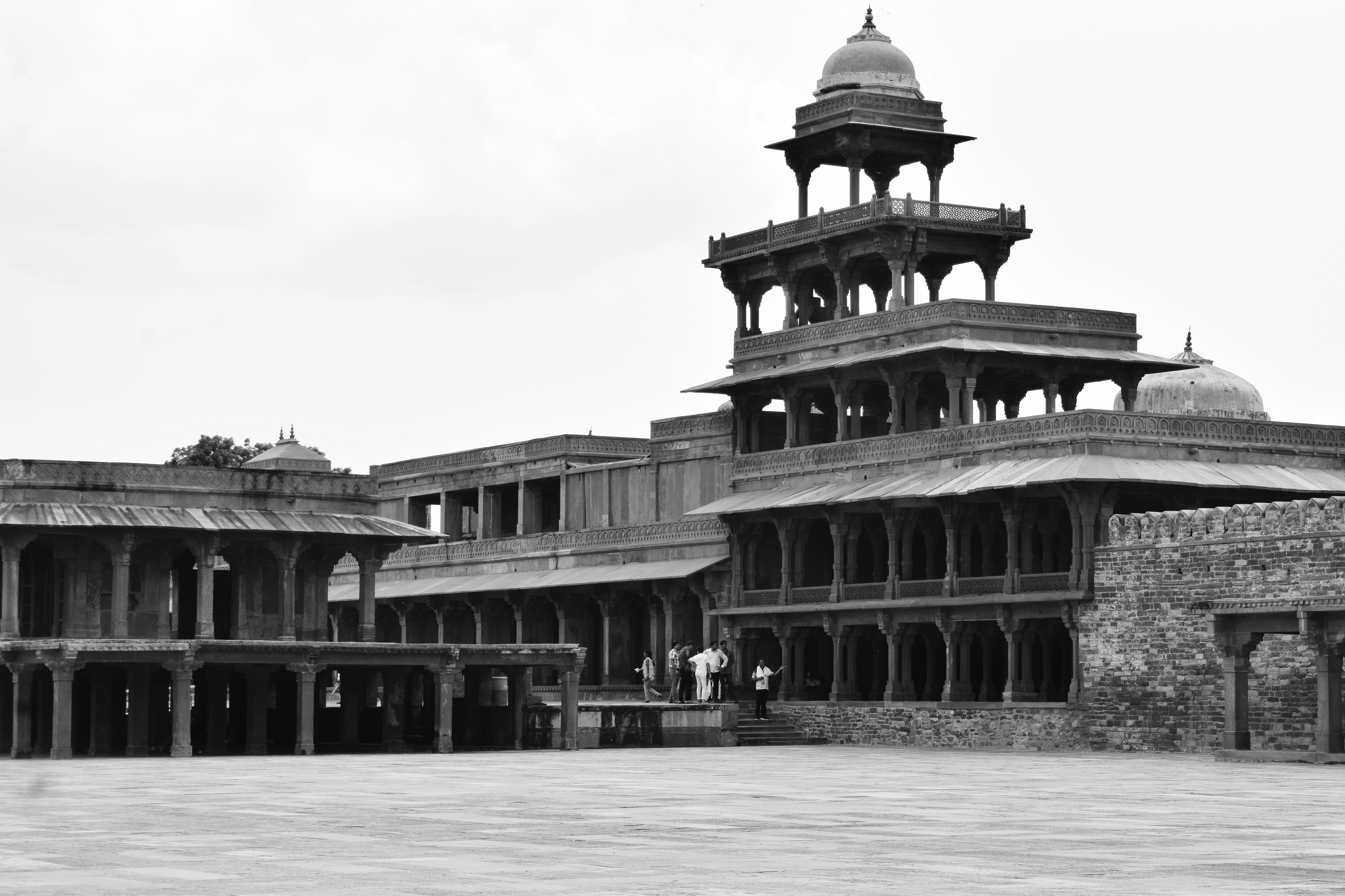 Intricate architecture of a historic building captured in monochrome, showcasing detailed arches and domes. Visitors explore the grandeur of the site.