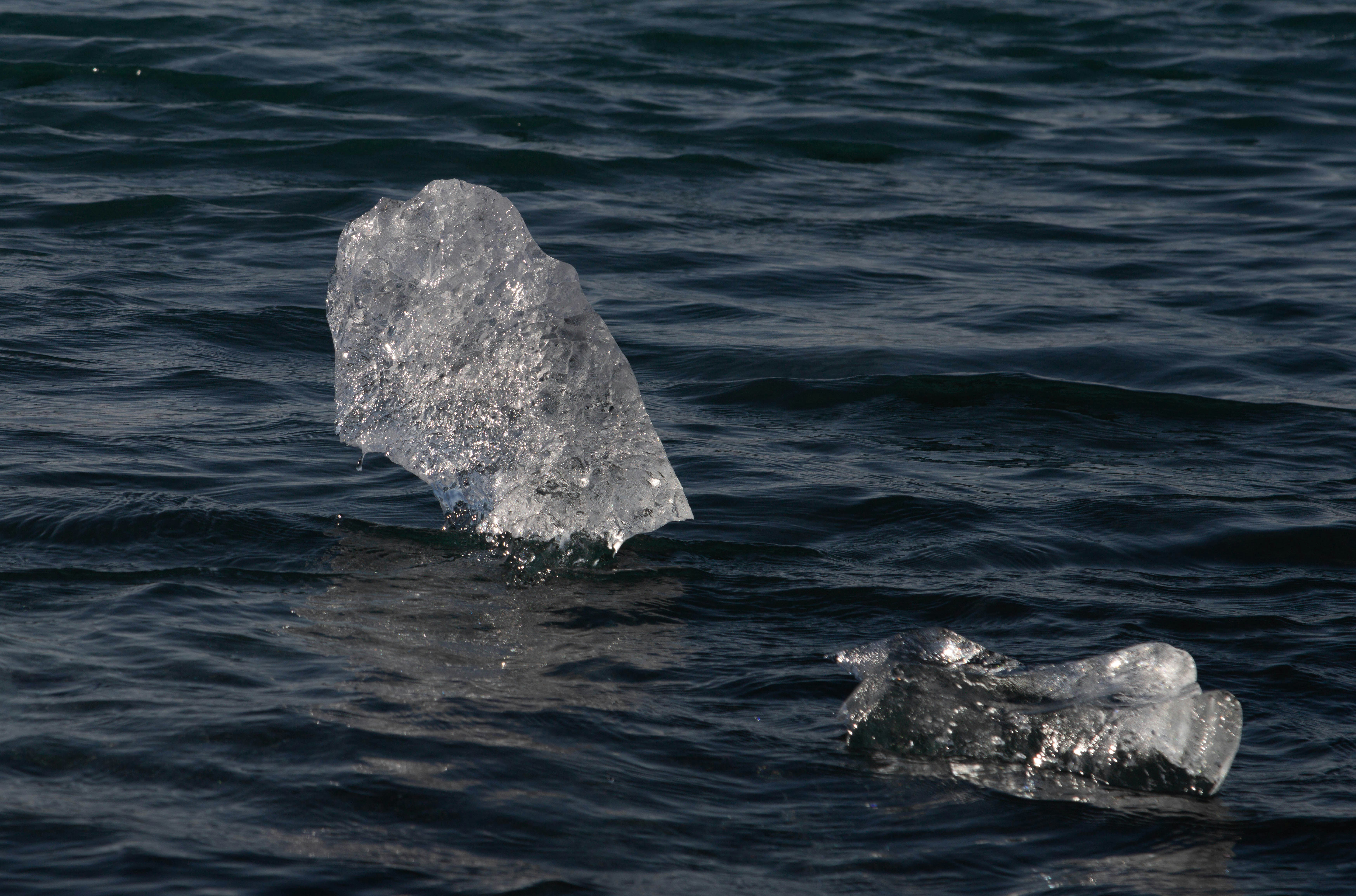 A Lone Ice Fragment Glints in a Deep Blue Sea