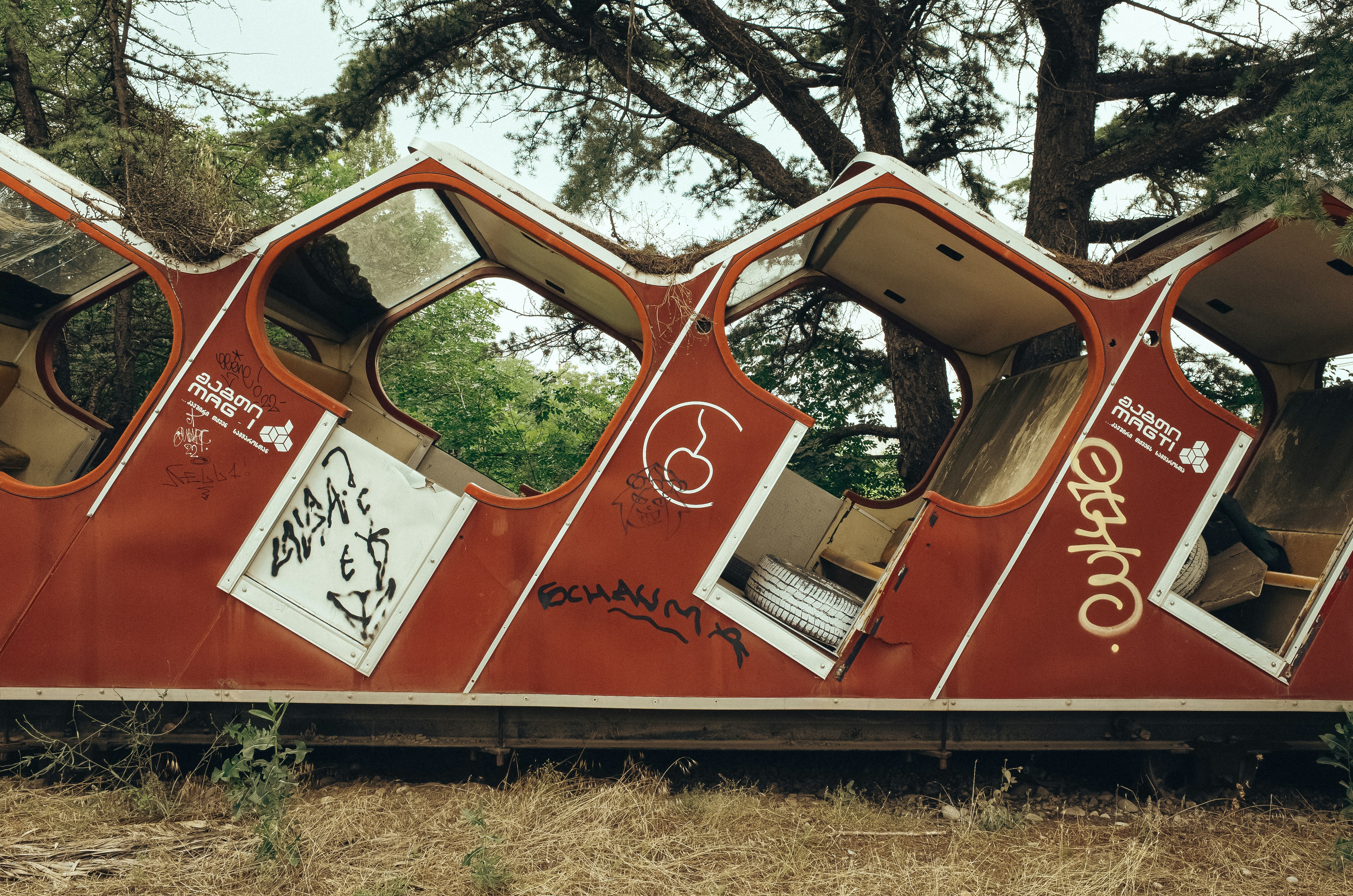 Leaning Red Carriages Beneath a Graffiti Skyline