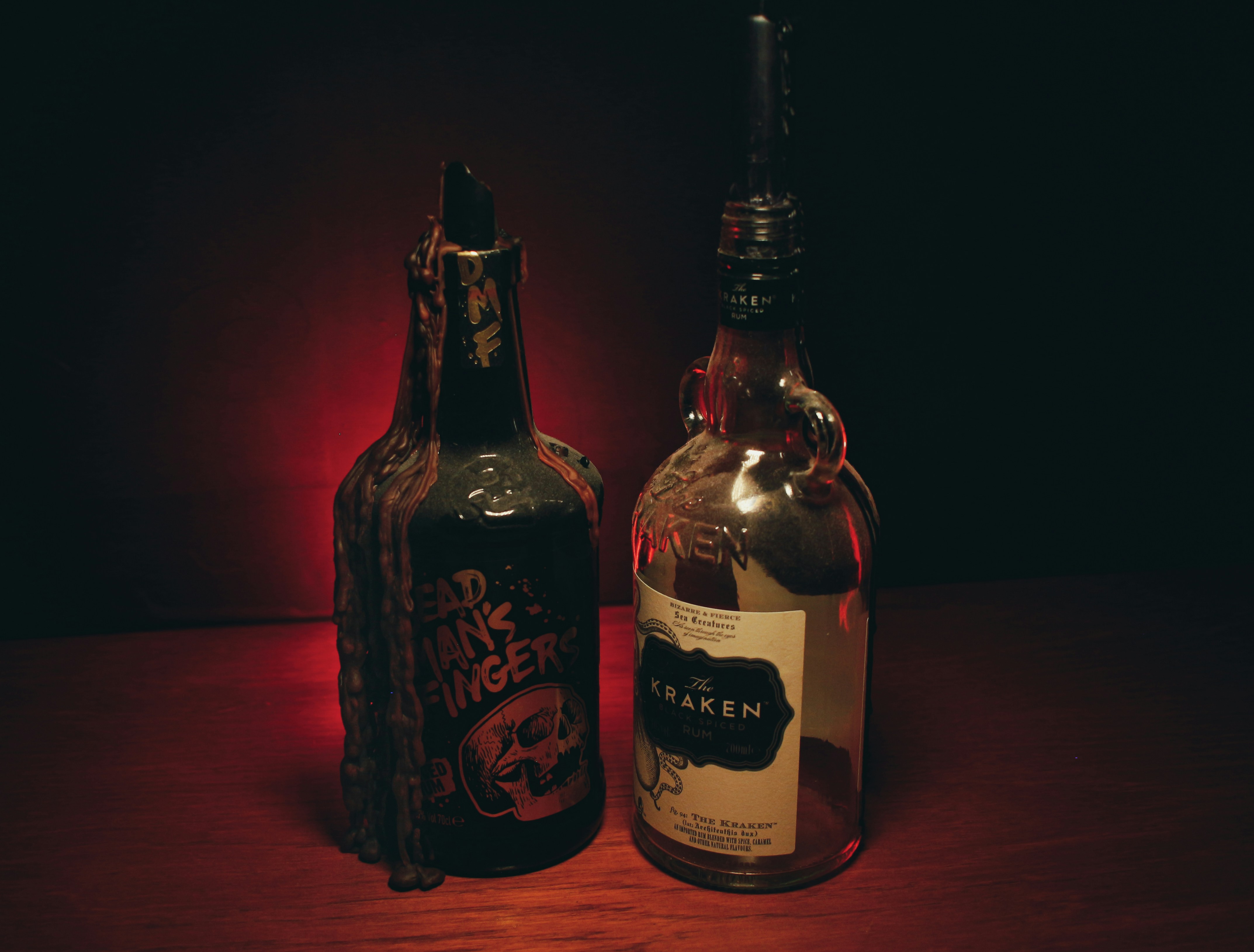 Two distinctive liquor bottles, one adorned with a skull motif and the other labeled 'The Kraken', set against a moody, illuminated backdrop.