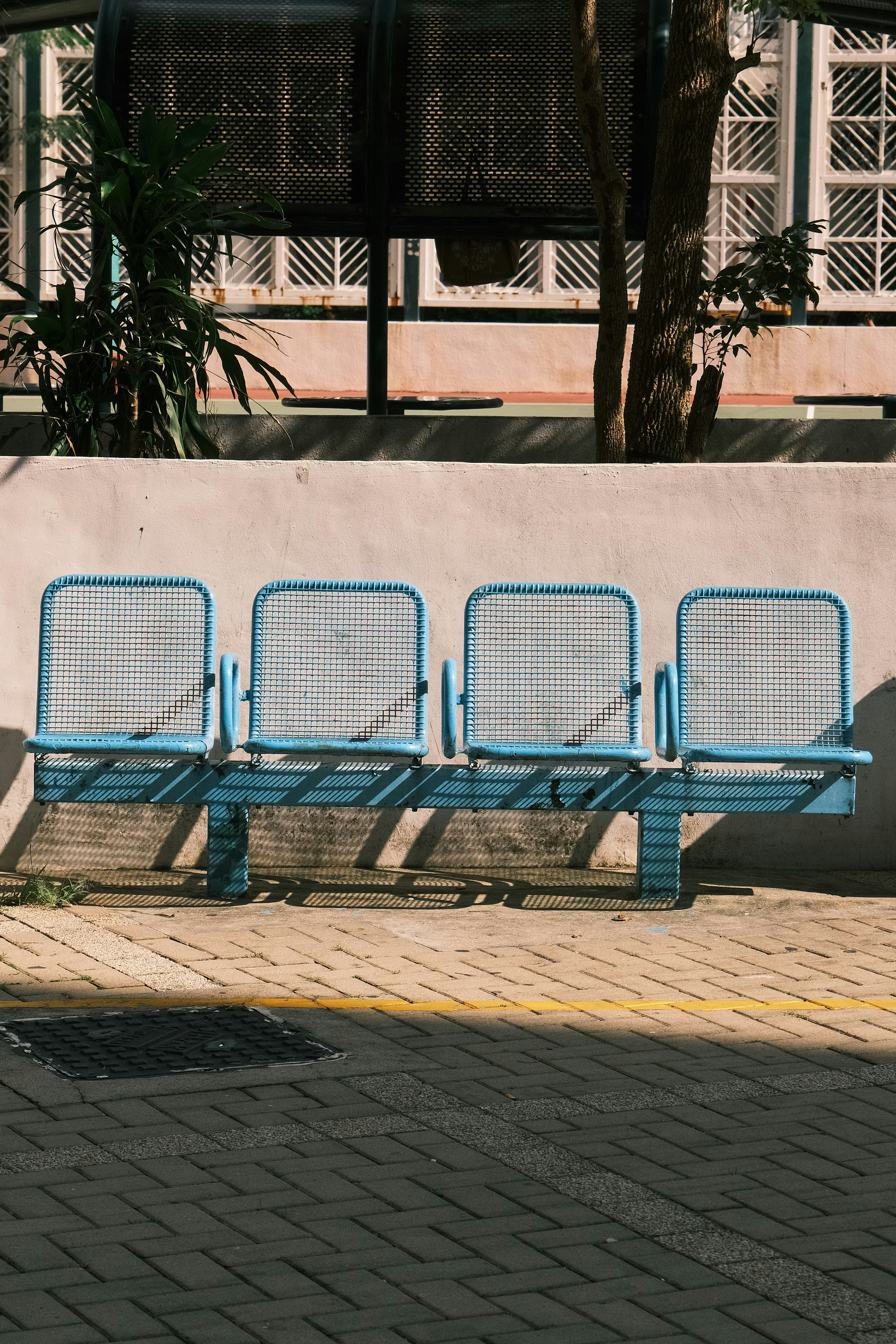 Cerulean Row: Sunlit Mesh Chairs in a Quiet Plaza