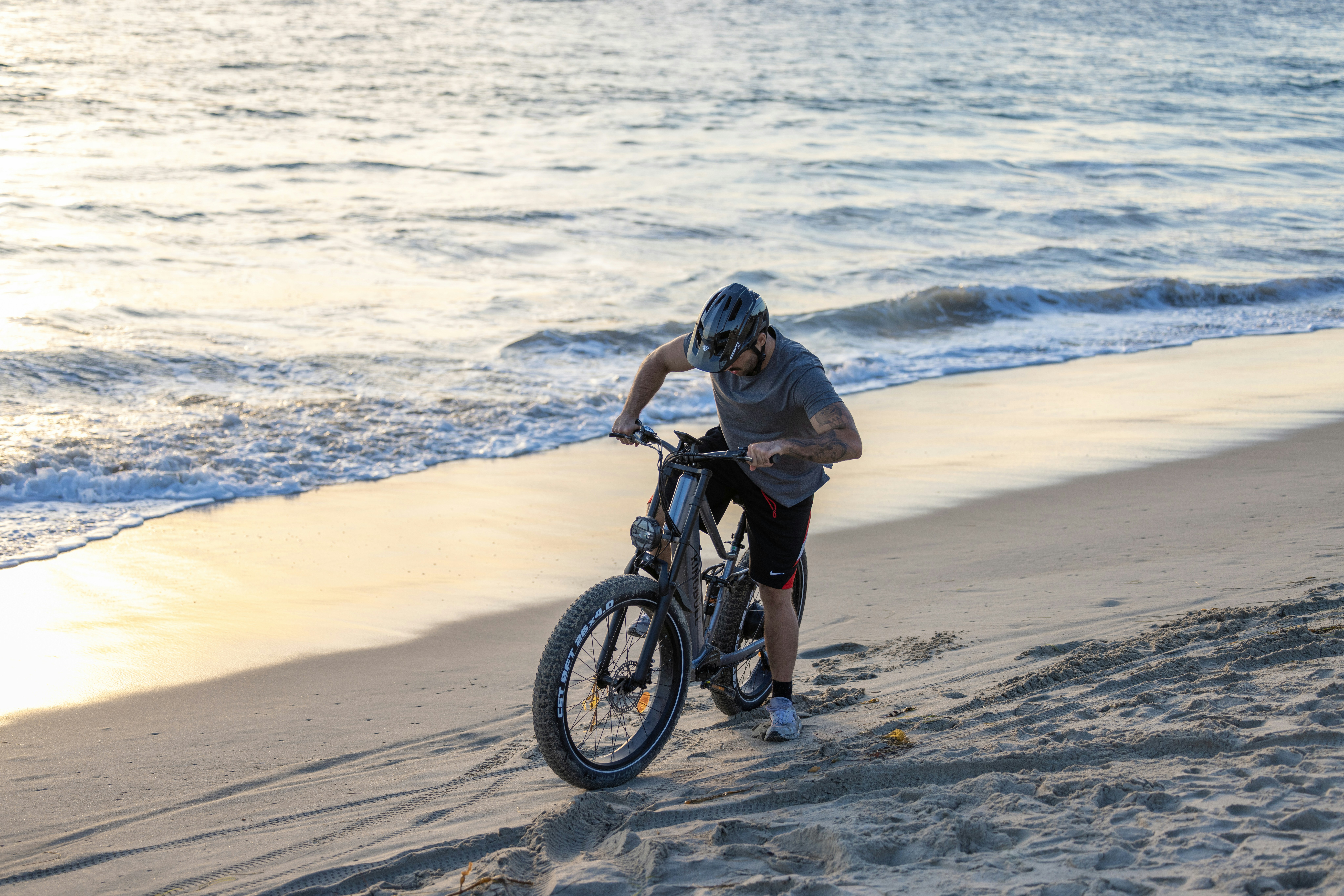 Shoreline Push: A cyclist navigates the beach at golden hour