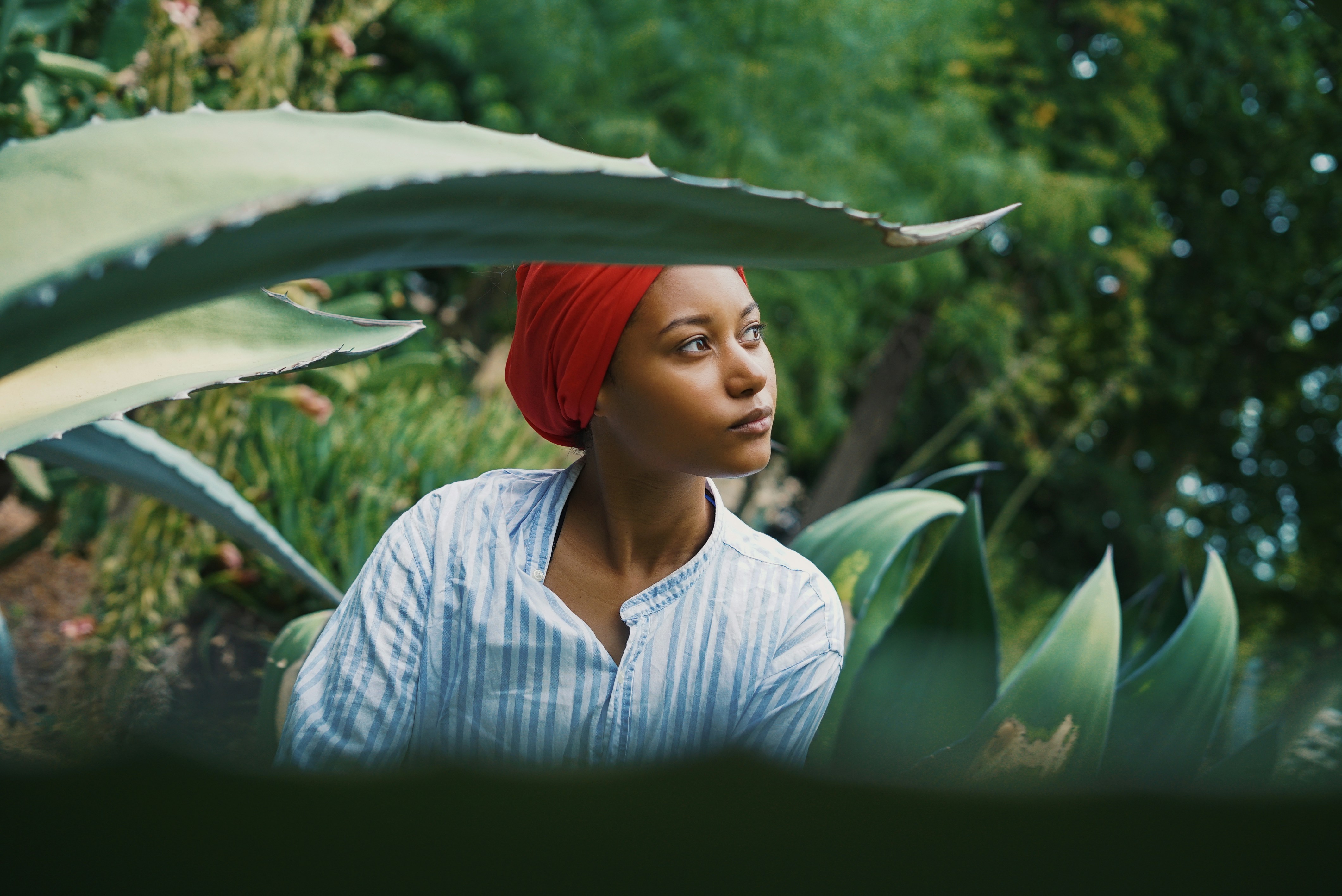 Crimson Turban, Quiet Gaze Amid Giant Leaves