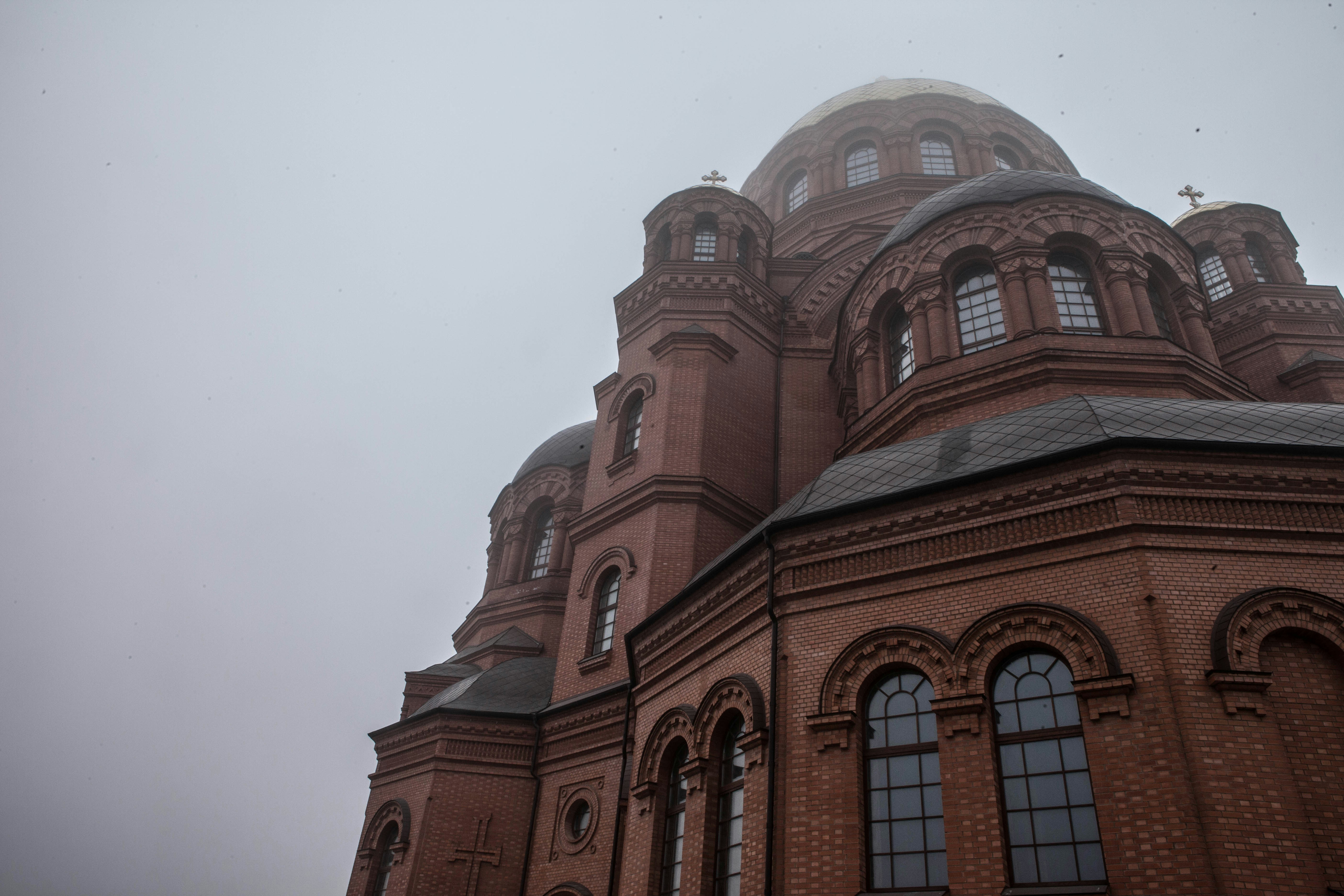 Dome-studded red-brick cathedral emerges from misty gray skies
