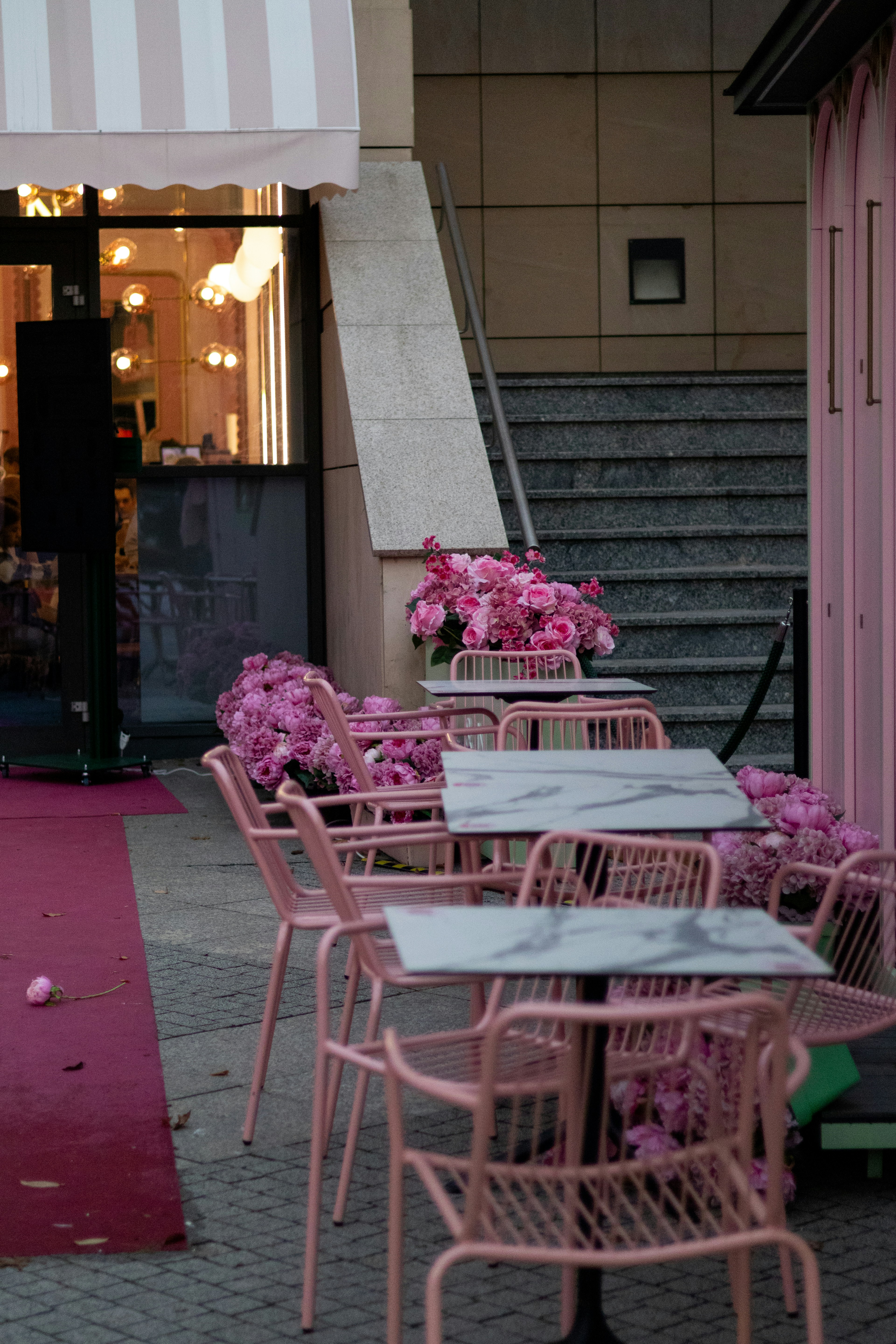 Pastel Threads of a City Café: Marble Tables, Pink Chairs, and Blooms by the Stairs