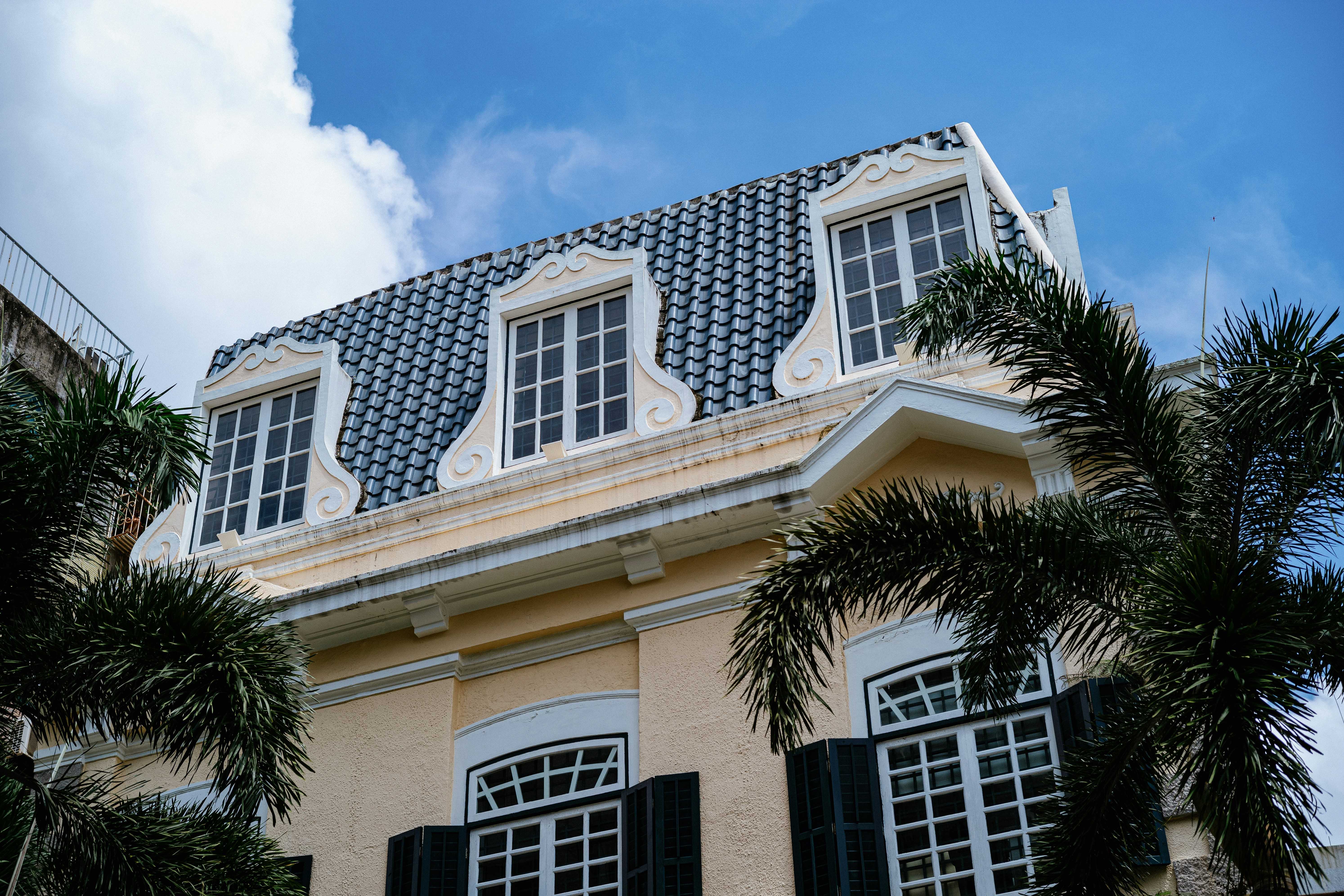 Azure Tile Roof Villa: Palm-Framed Facade Under Caribbean Sky