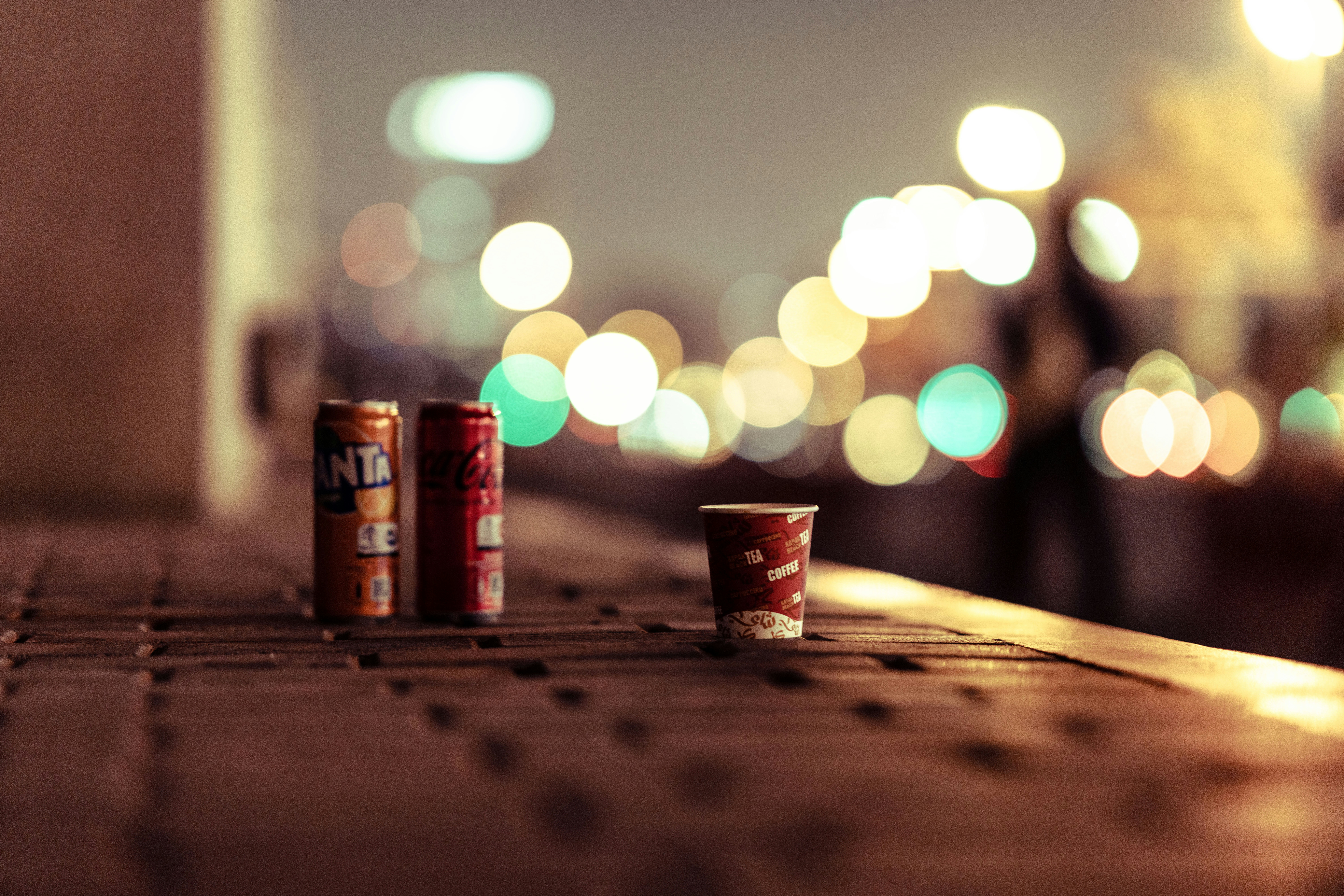 Two Cans, One Cup: A Warm Bokeh Night on a City Street
