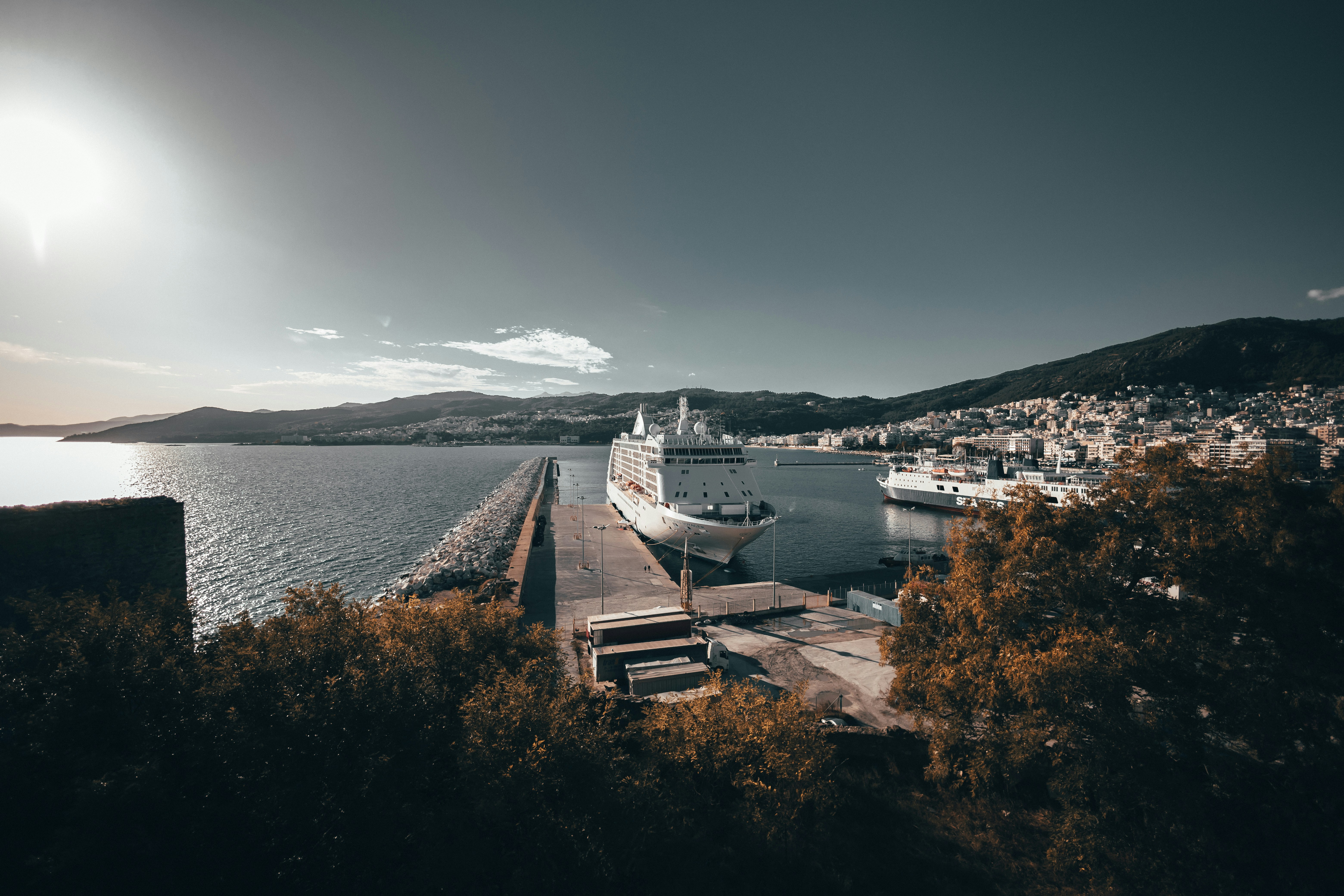 Pier to the Quiet Harbor: Boats, sunlit water, and a hillside town