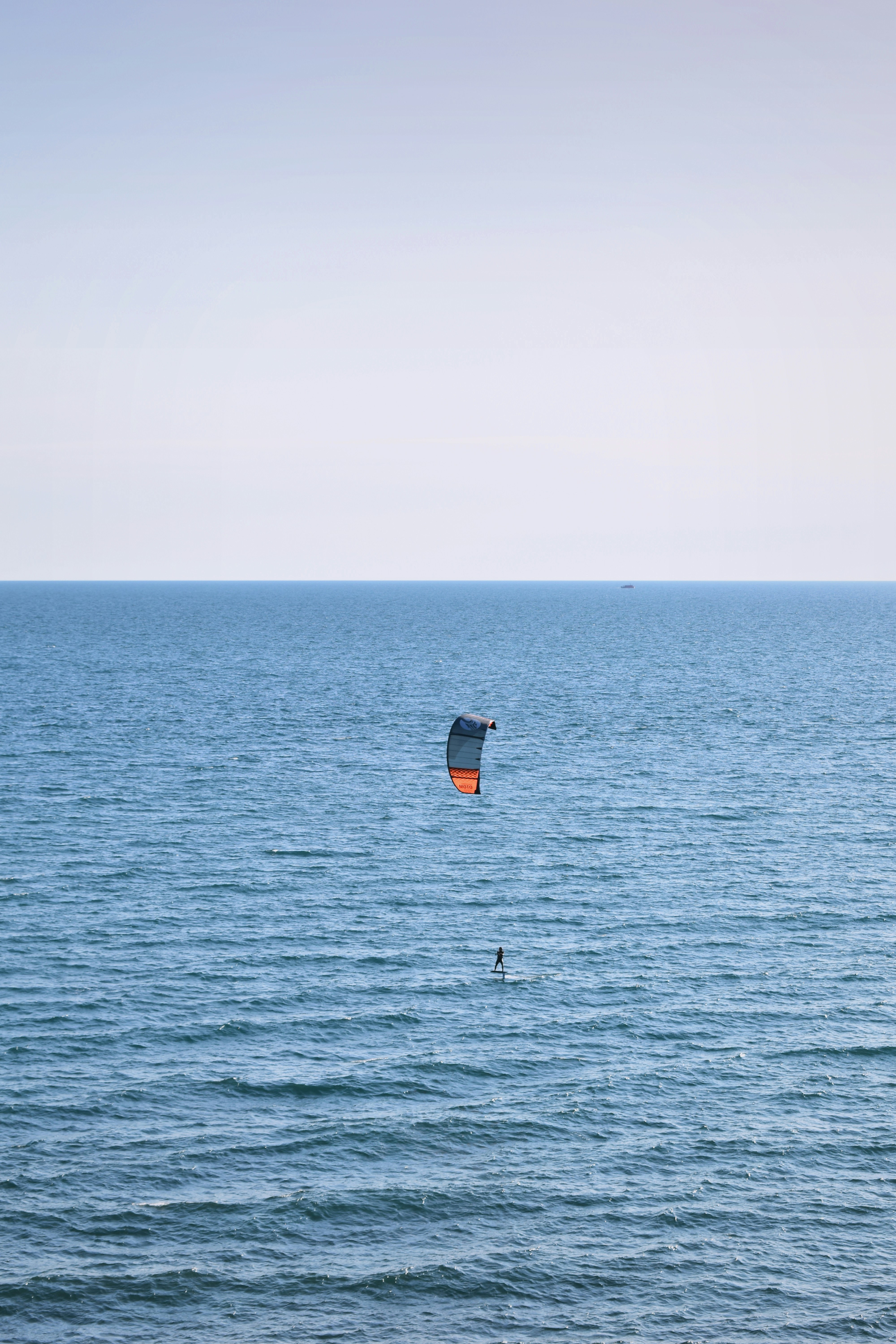 Azure Wake: Kite Surfer Carving Quiet Ocean Blues