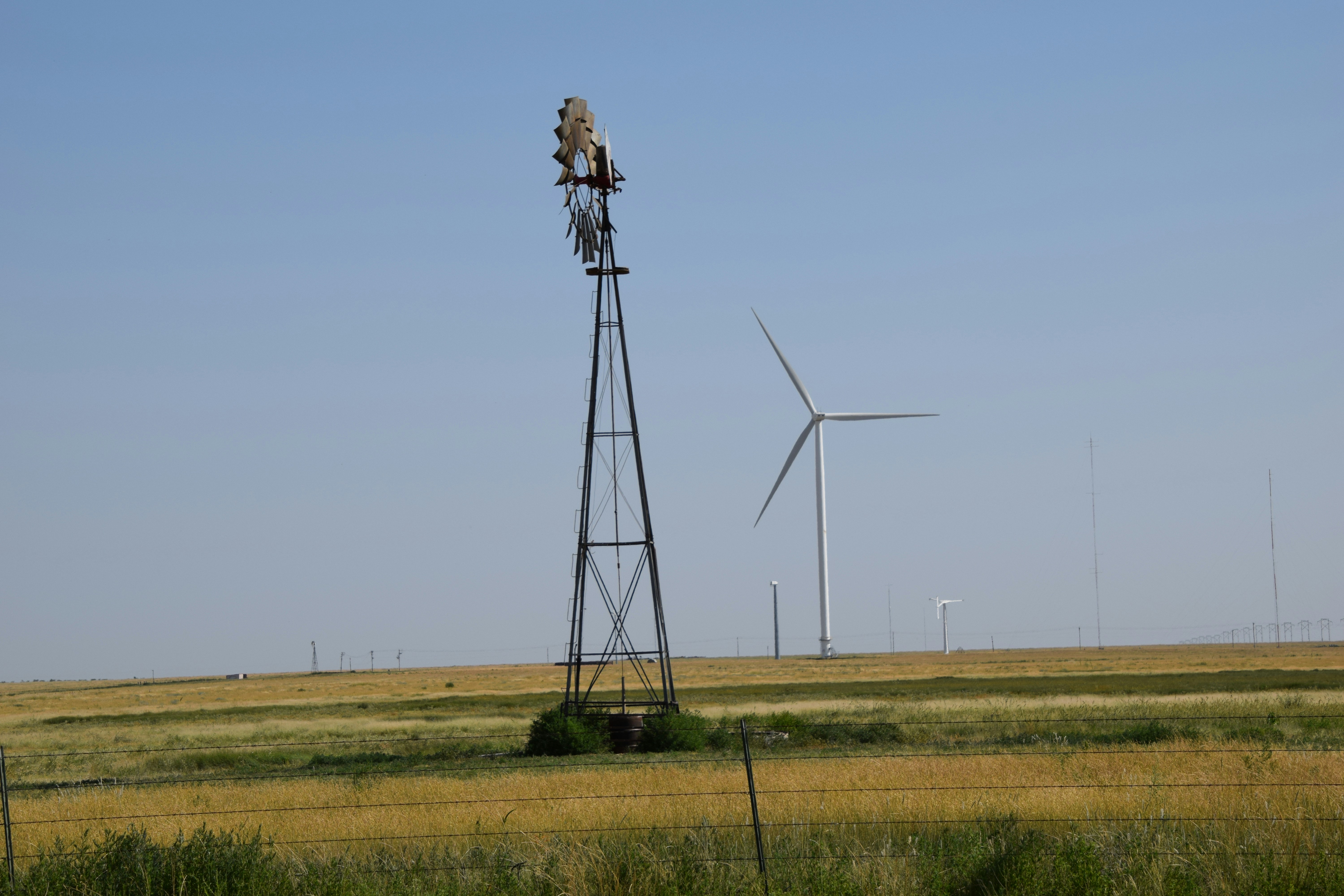 Lattice Sentinel over the Prairie: Foreground Tower and Distant Turbines