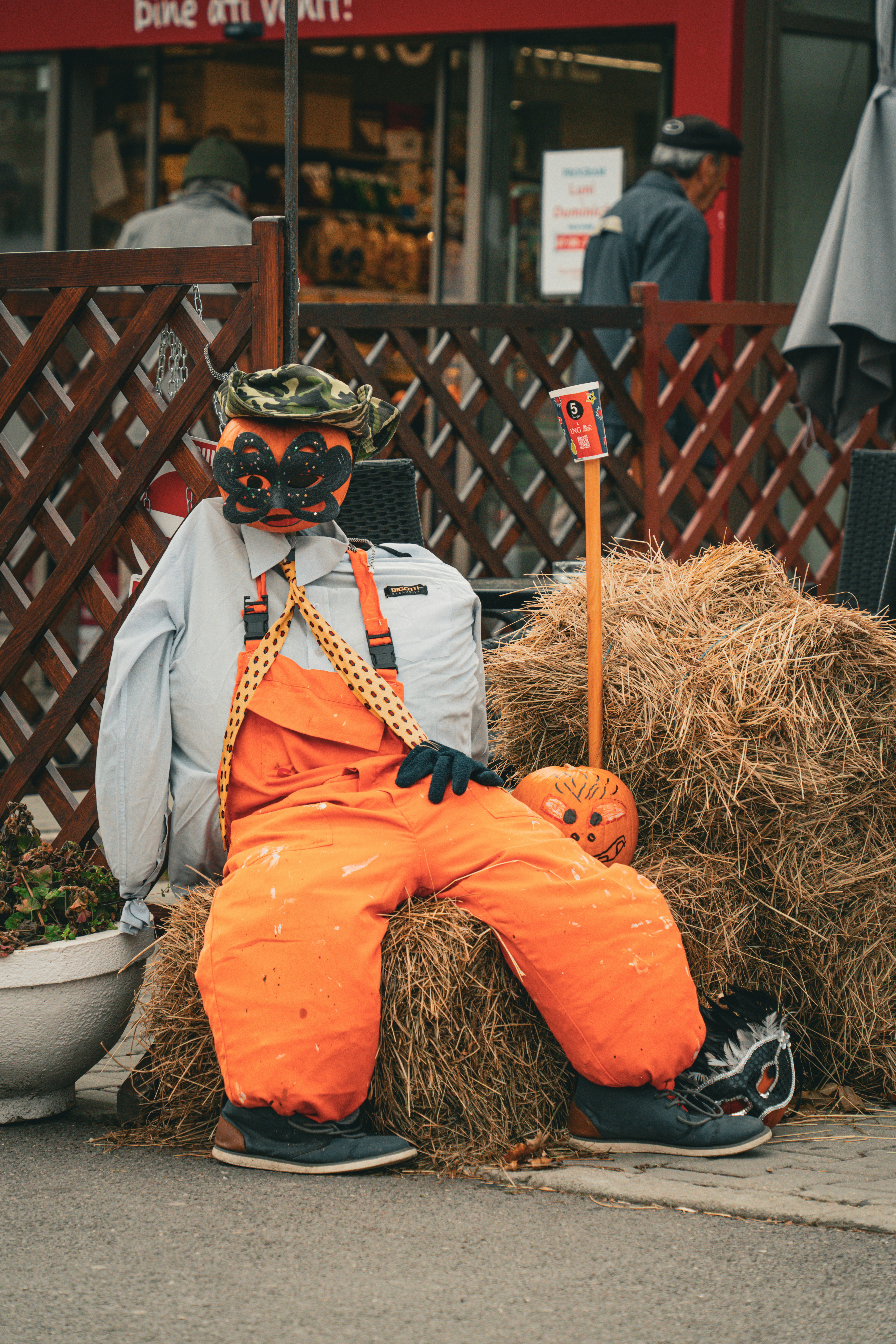 Harvest Haunt: A masked scarecrow lounging by hay and pumpkin