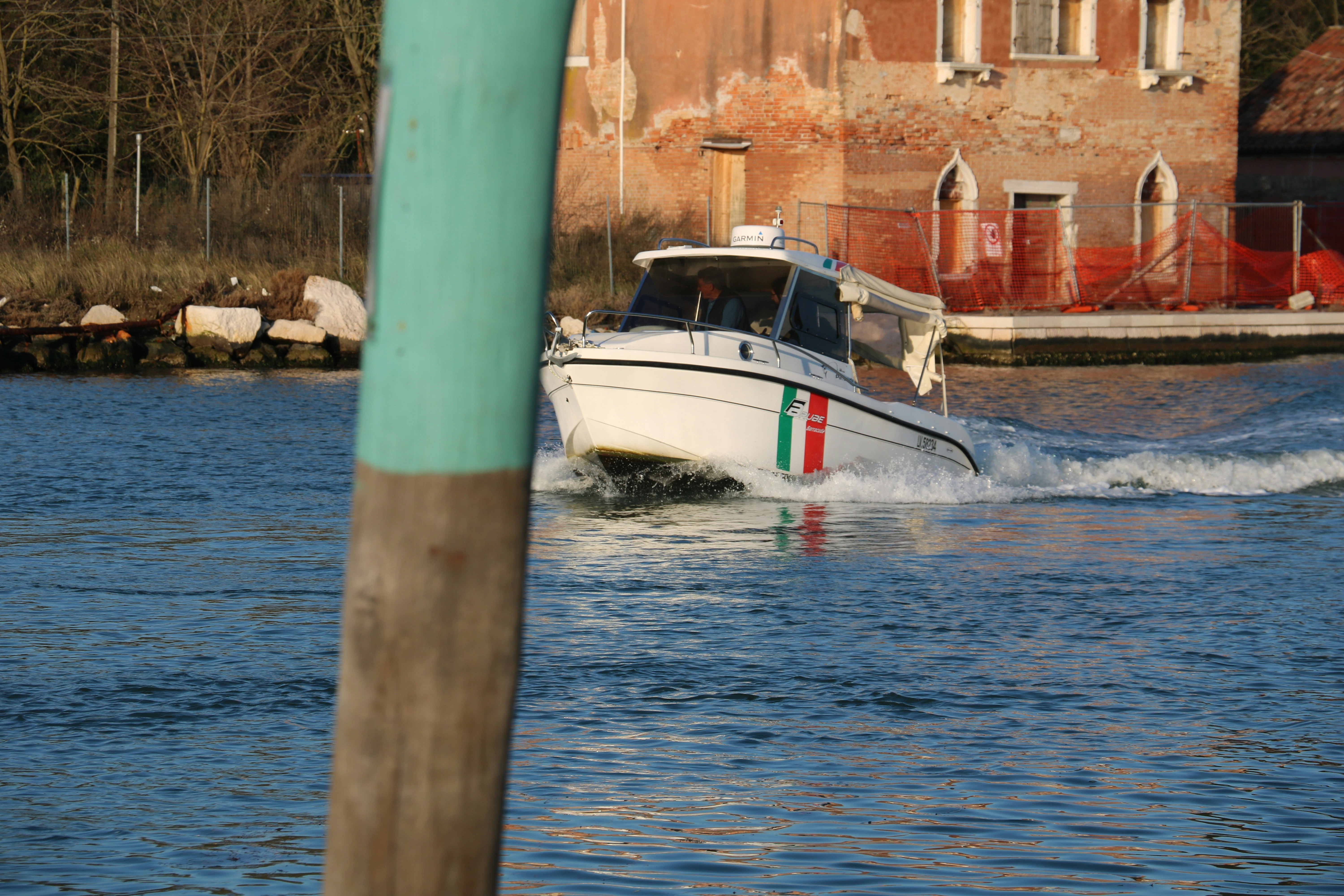 Speedboat navigating a canal with historic architecture in the background.