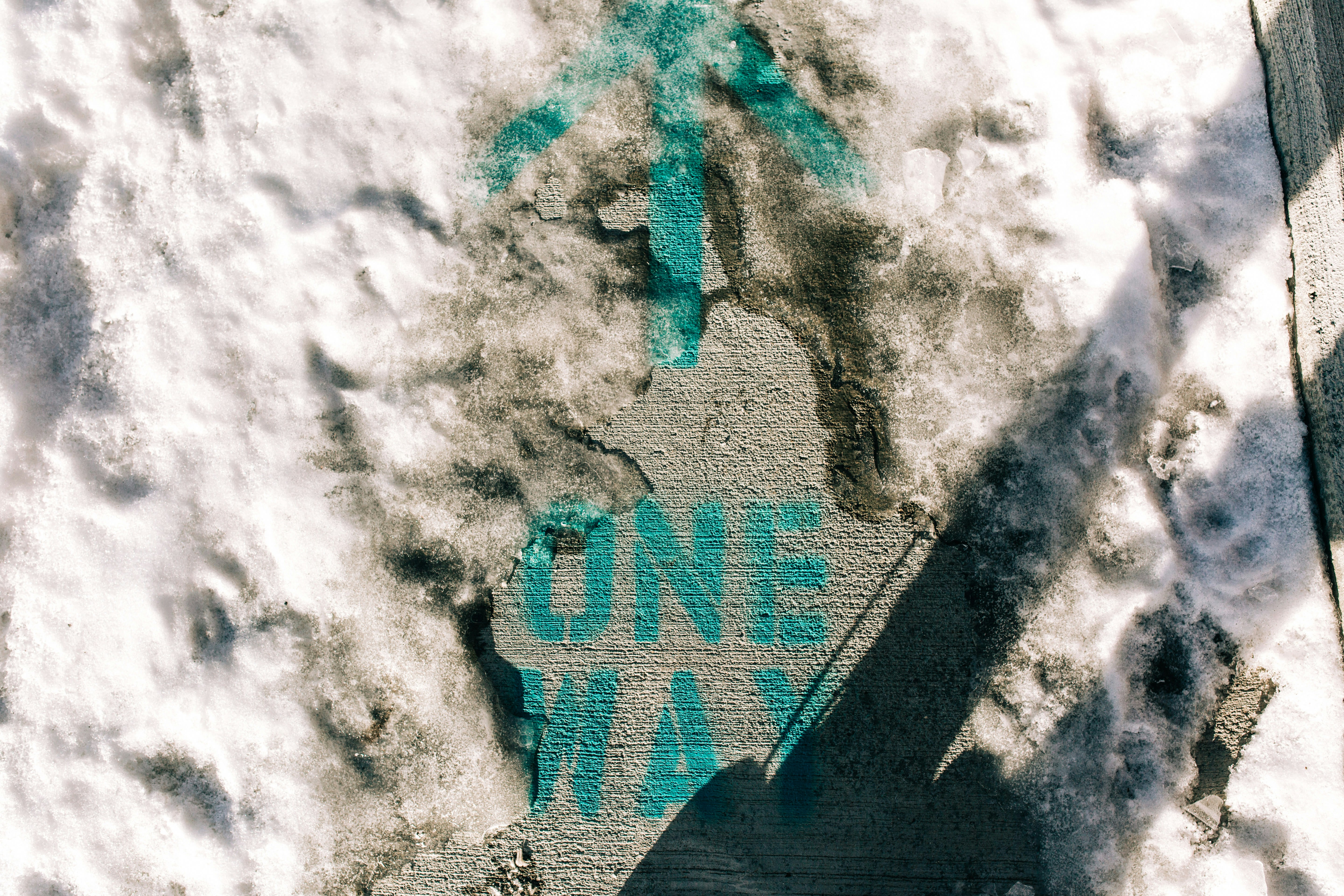 One Way in Sunlit Grit: Turquoise Graffiti on Weathered Concrete