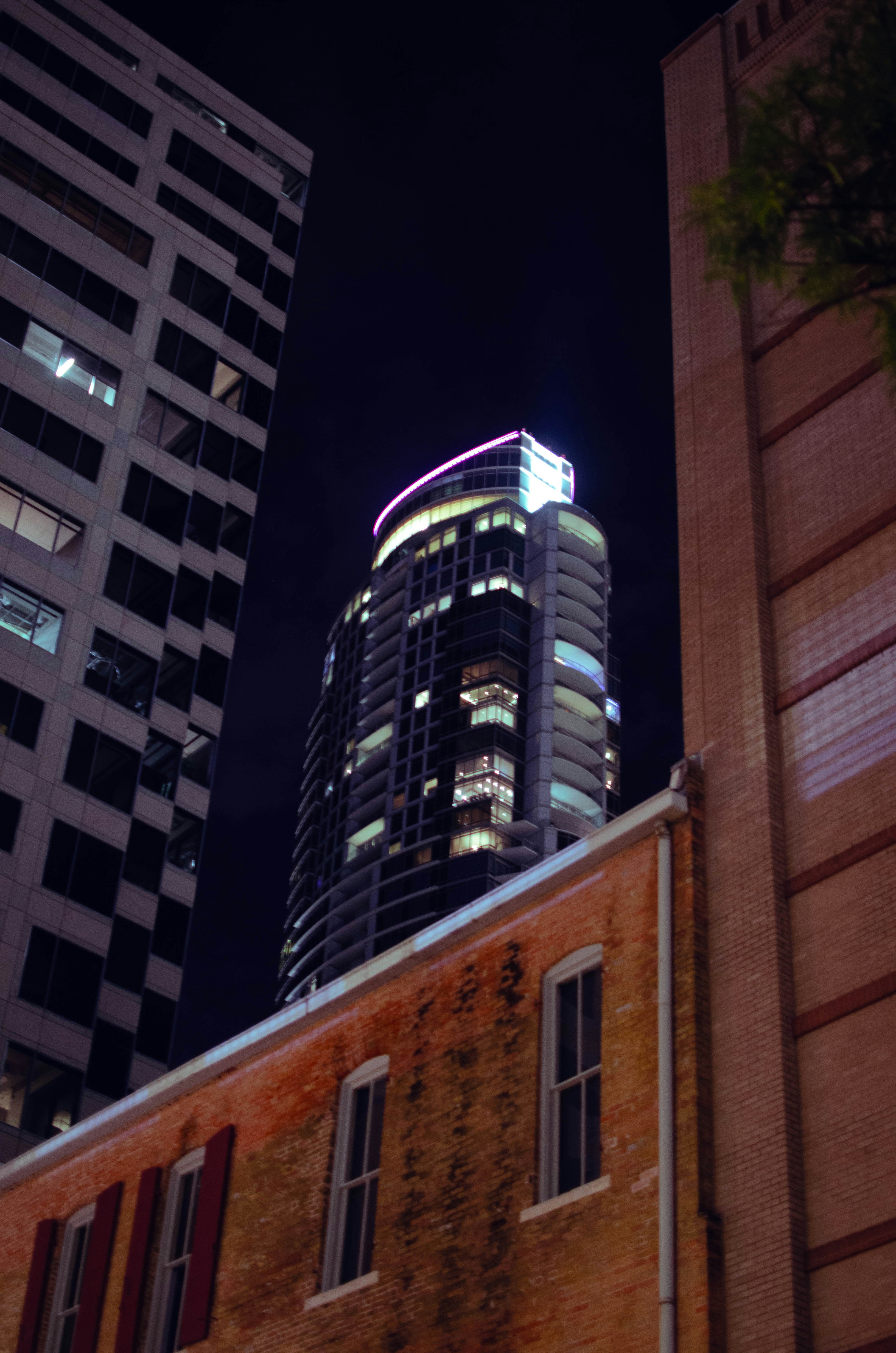 Neon-Crowned Glass Tower Rising Over a Night Brickscape