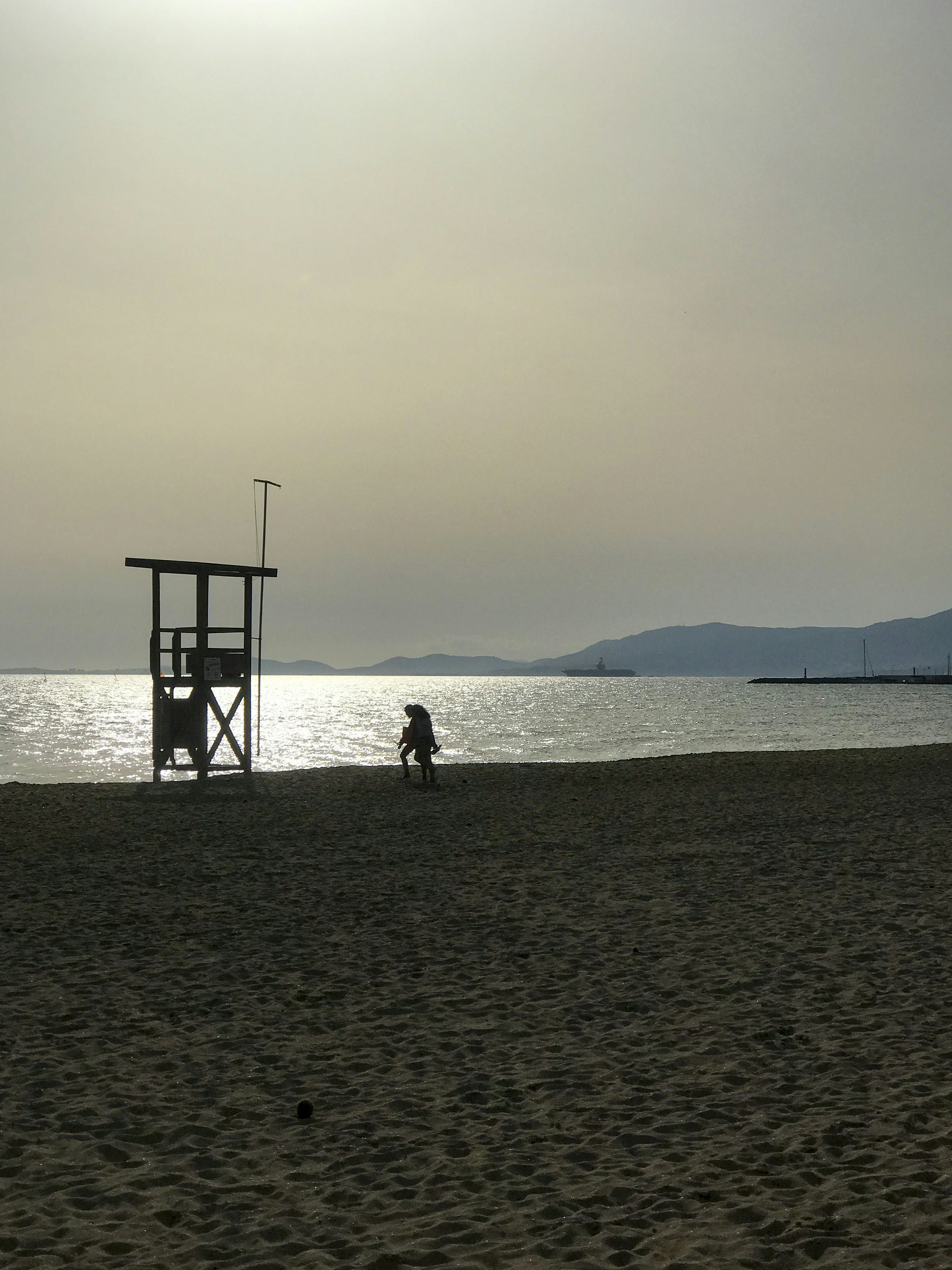 Dusk on the Quiet Beach: Silhouetted Lifeguard Tower and Jogger
