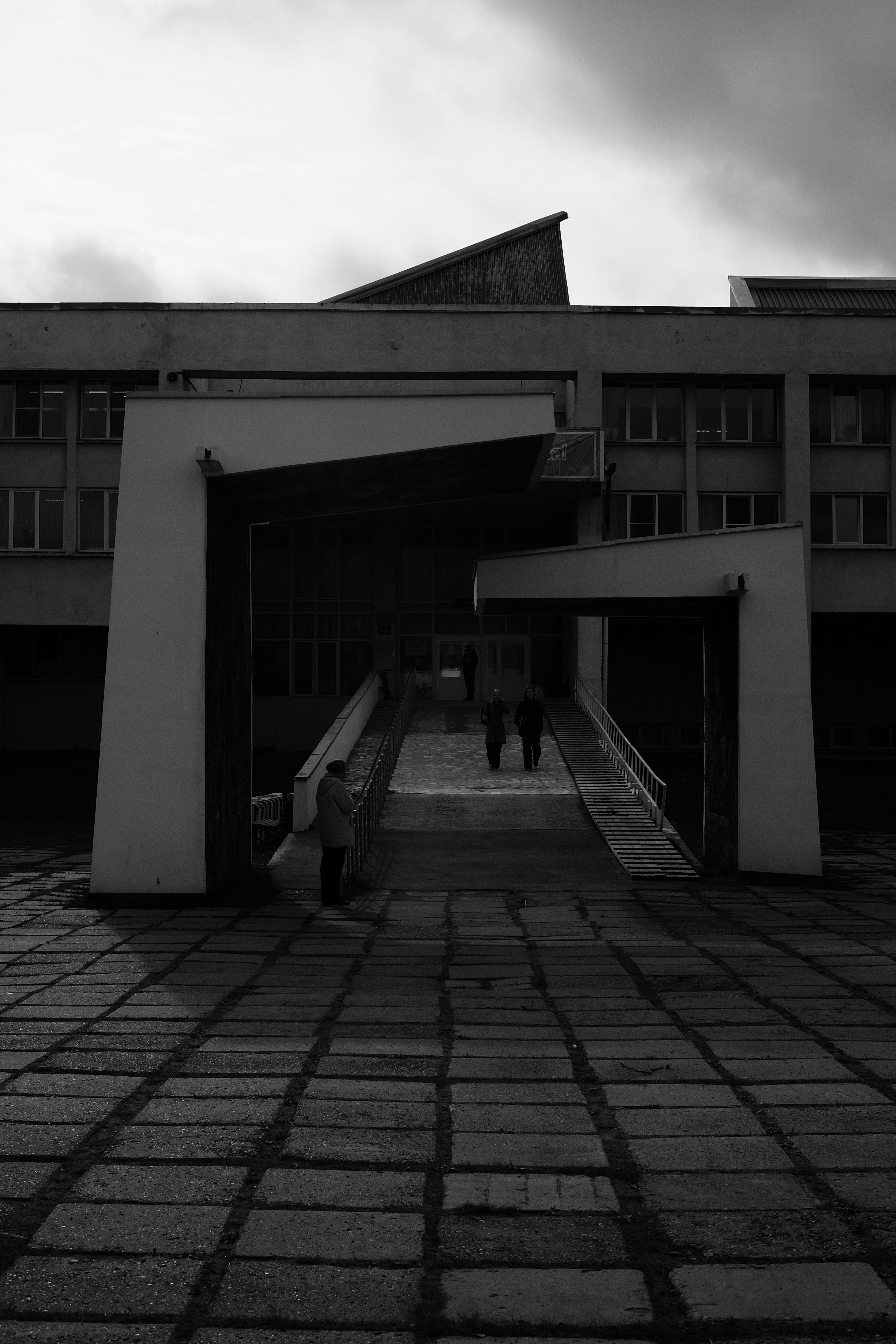 A black and white photo of two people walking down a walkway photo ...