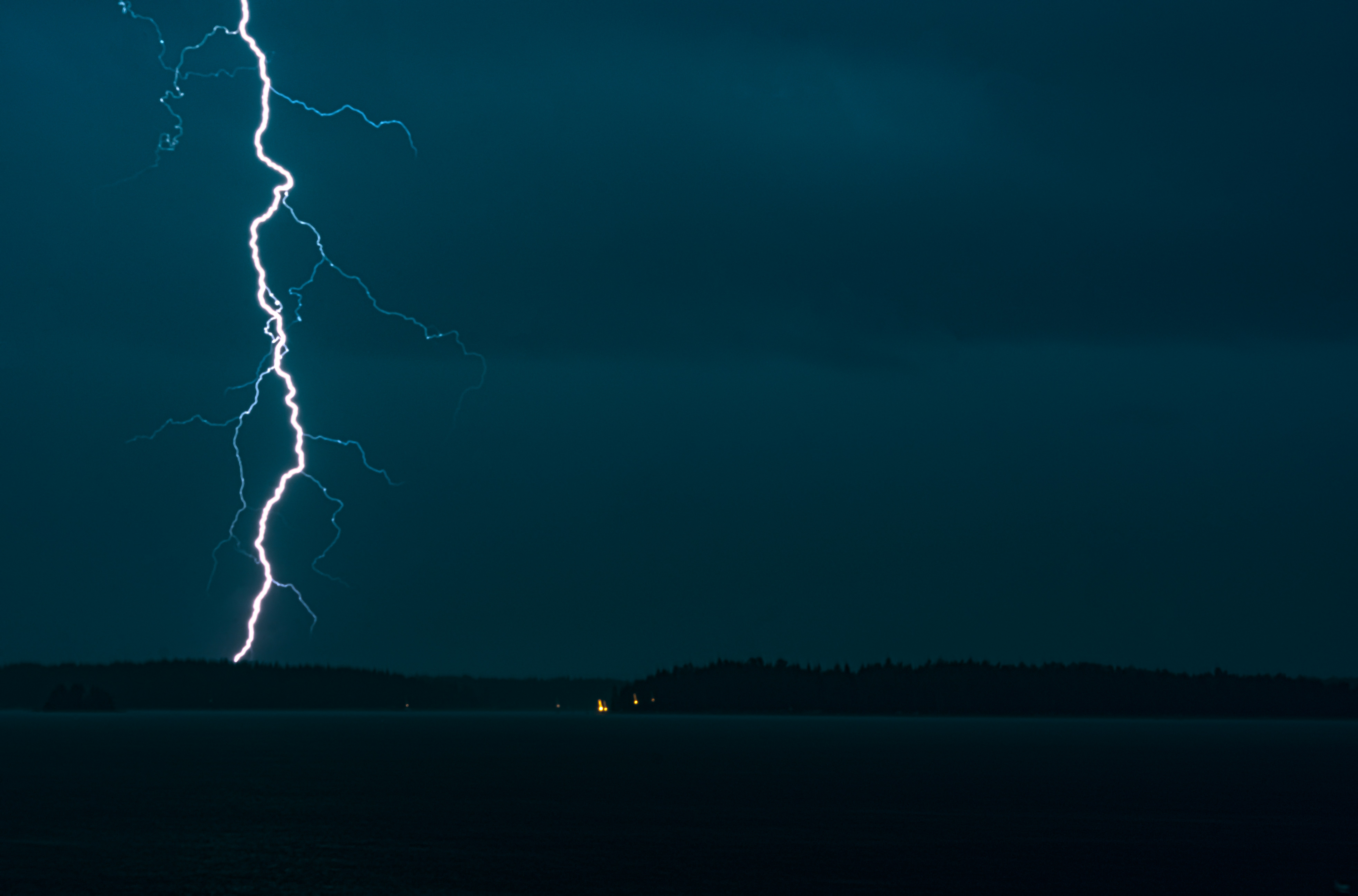 A lightning bolt strikes across the sky over a body of water photo ...