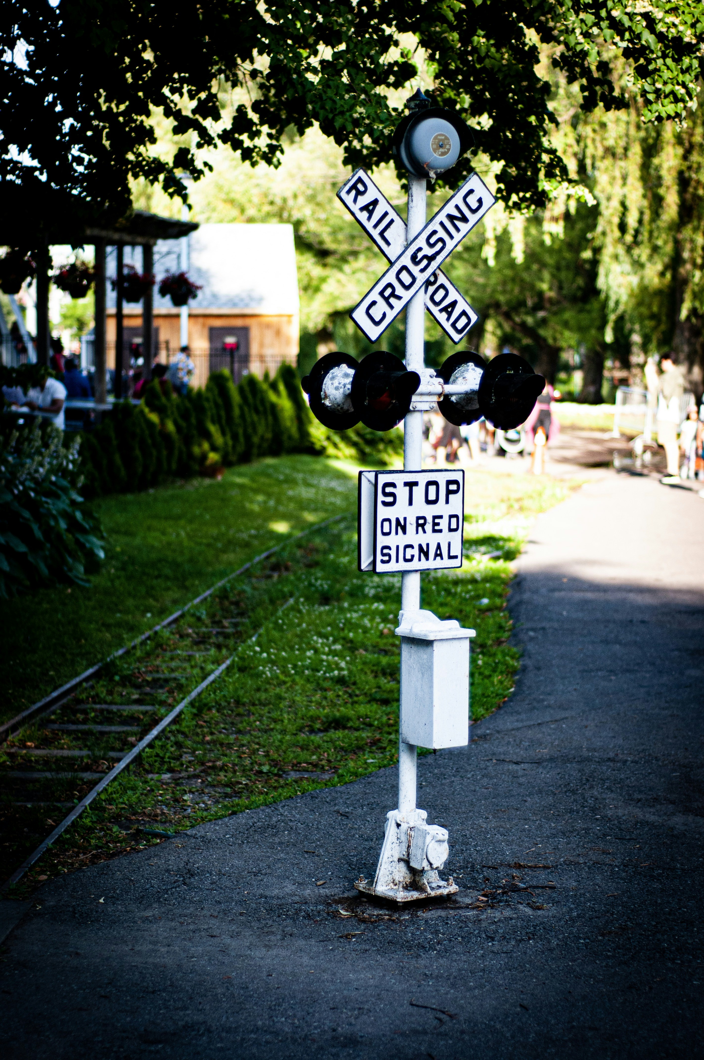 The Quiet Crossing: A Weathered Railroad Signal by a Sunlit Park Path