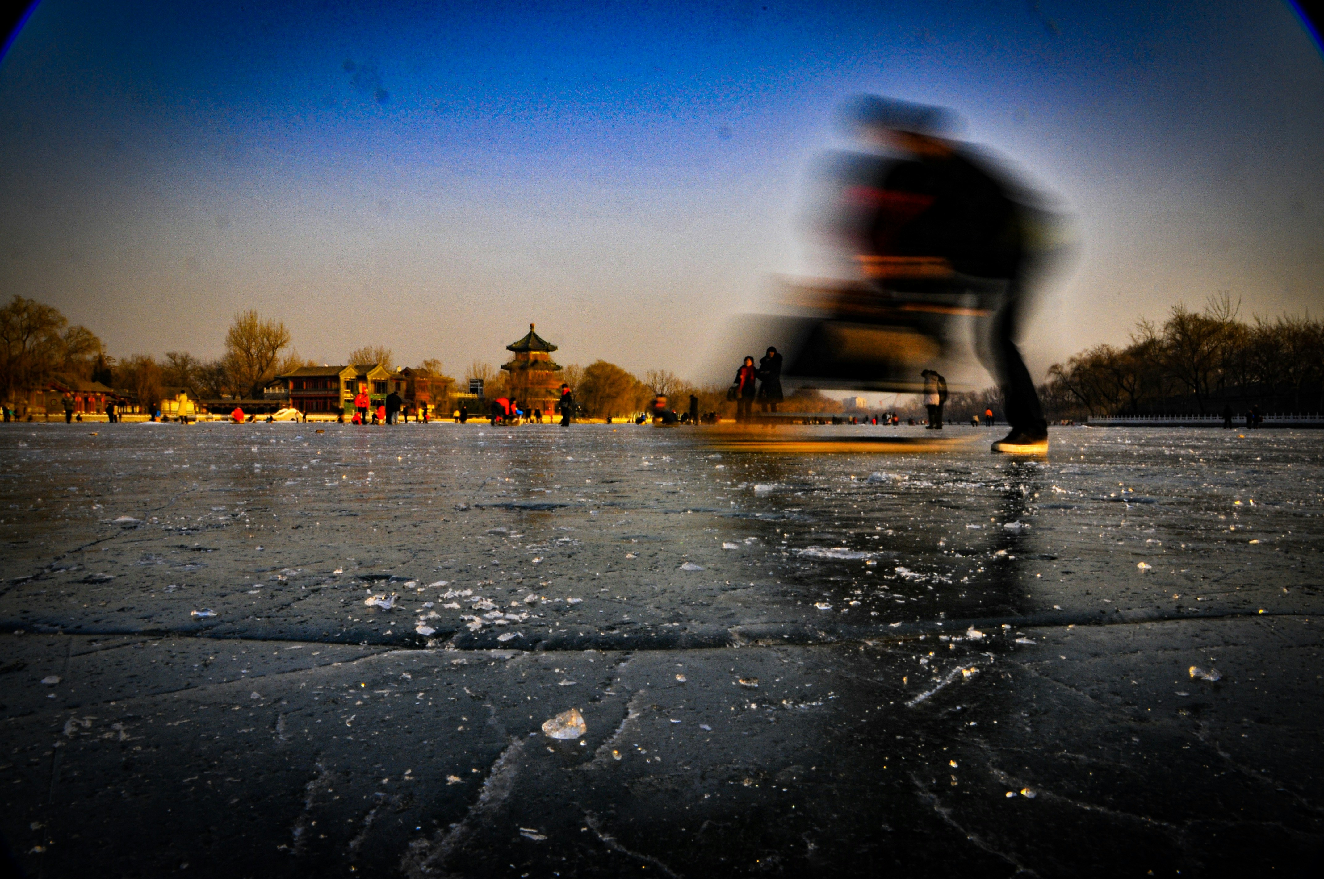 Beneath Frozen Echoes: Blurred Skateboarders Over a Century-Old Park Pond