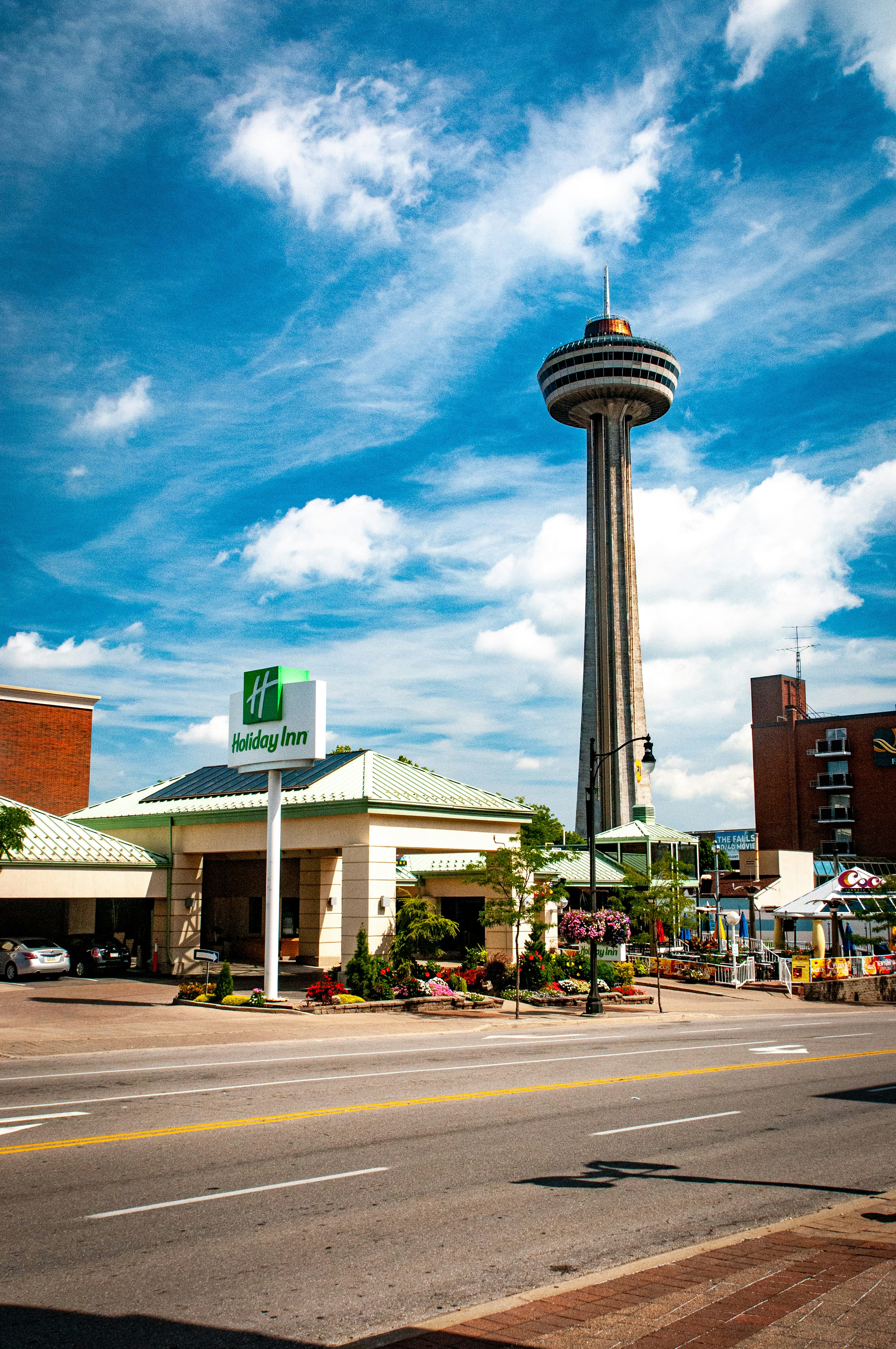 Tower Over Main Street: A sunlit cityscape framed by a circular observation tower and a Holiday Inn sign