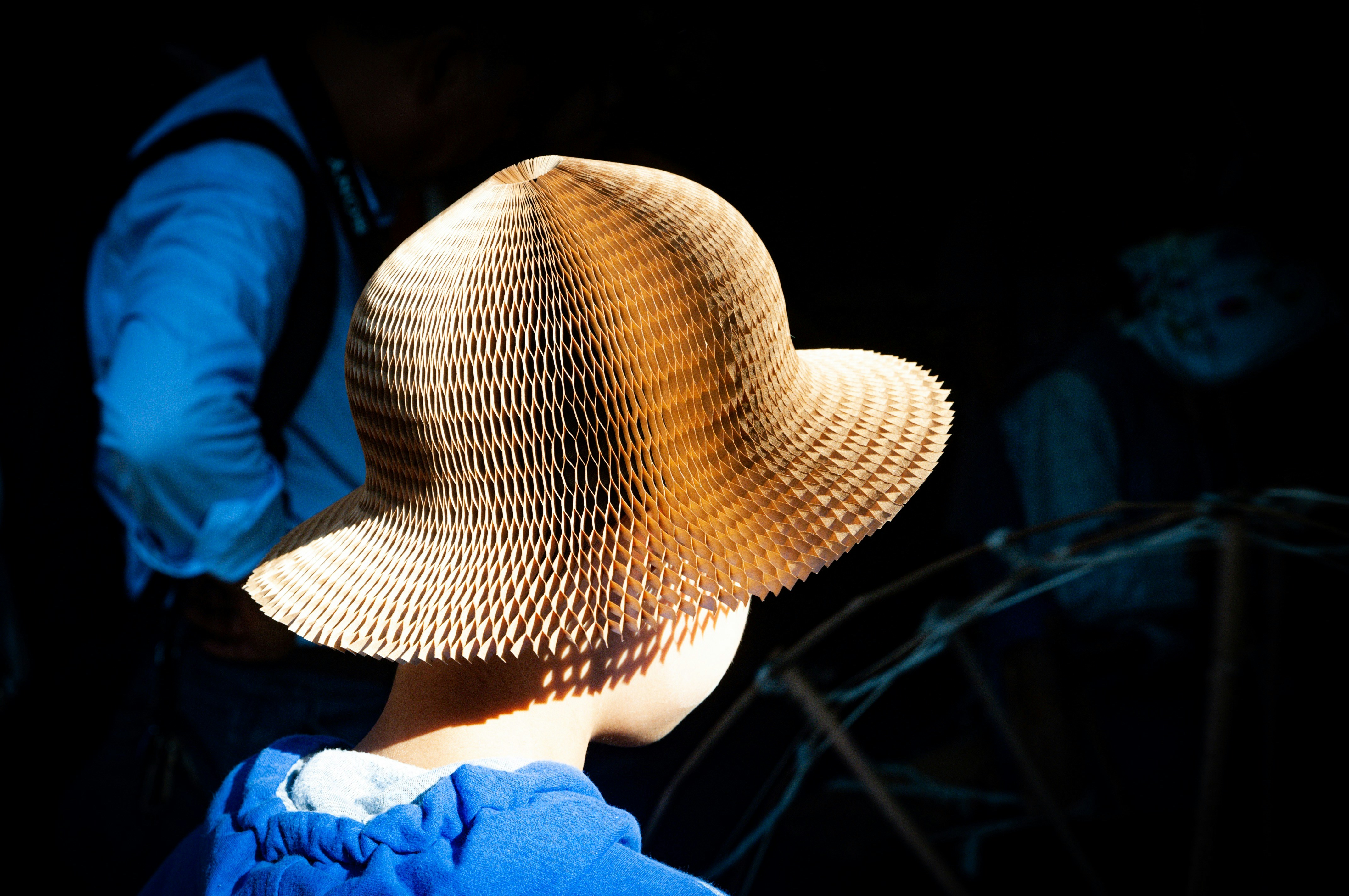 Sun-Kissed Weave: a straw hat lighting up a blue-clad figure in shadow