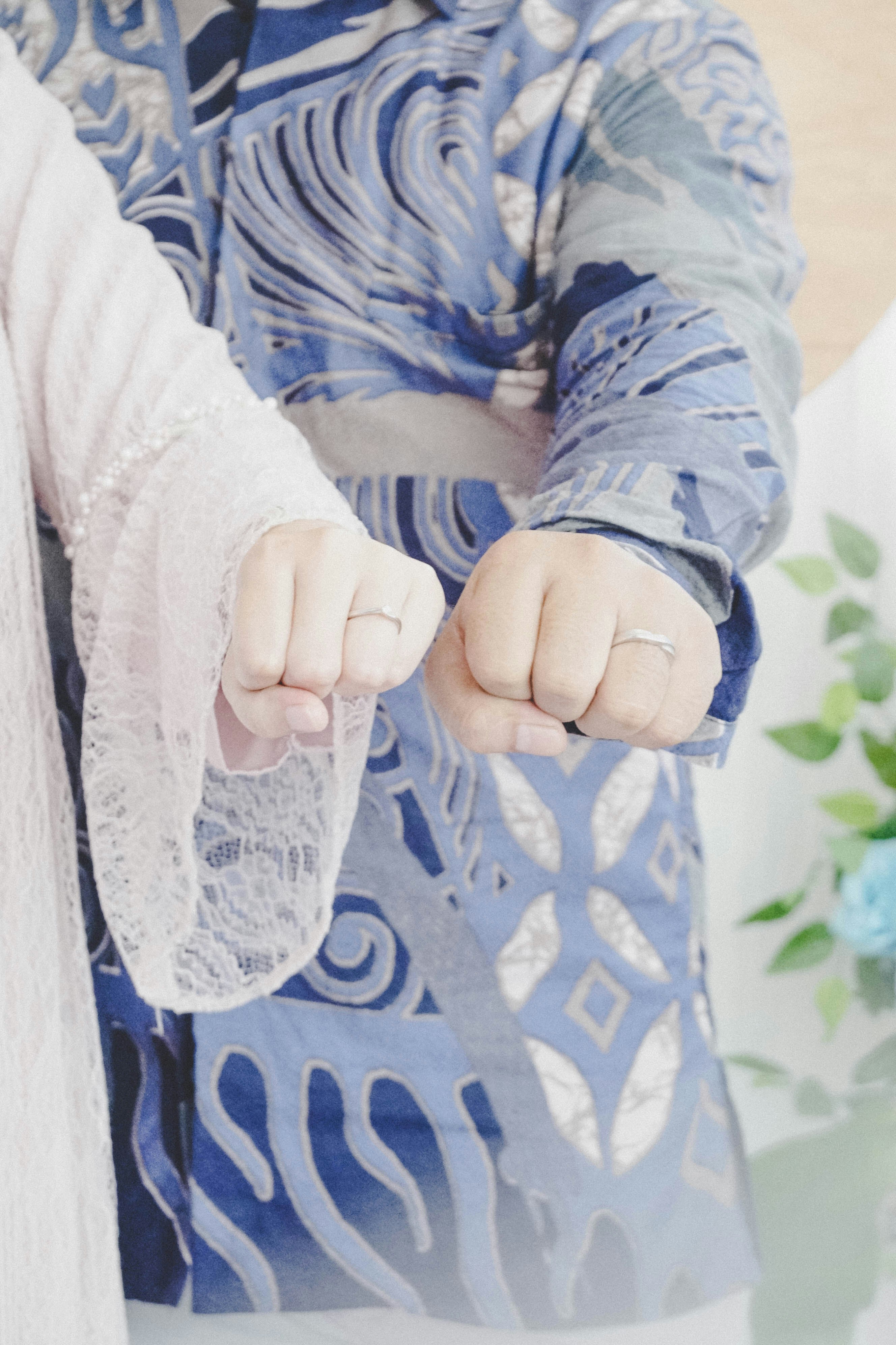 Rings at Rest: a close-up fist bump in soft lace and blue pattern