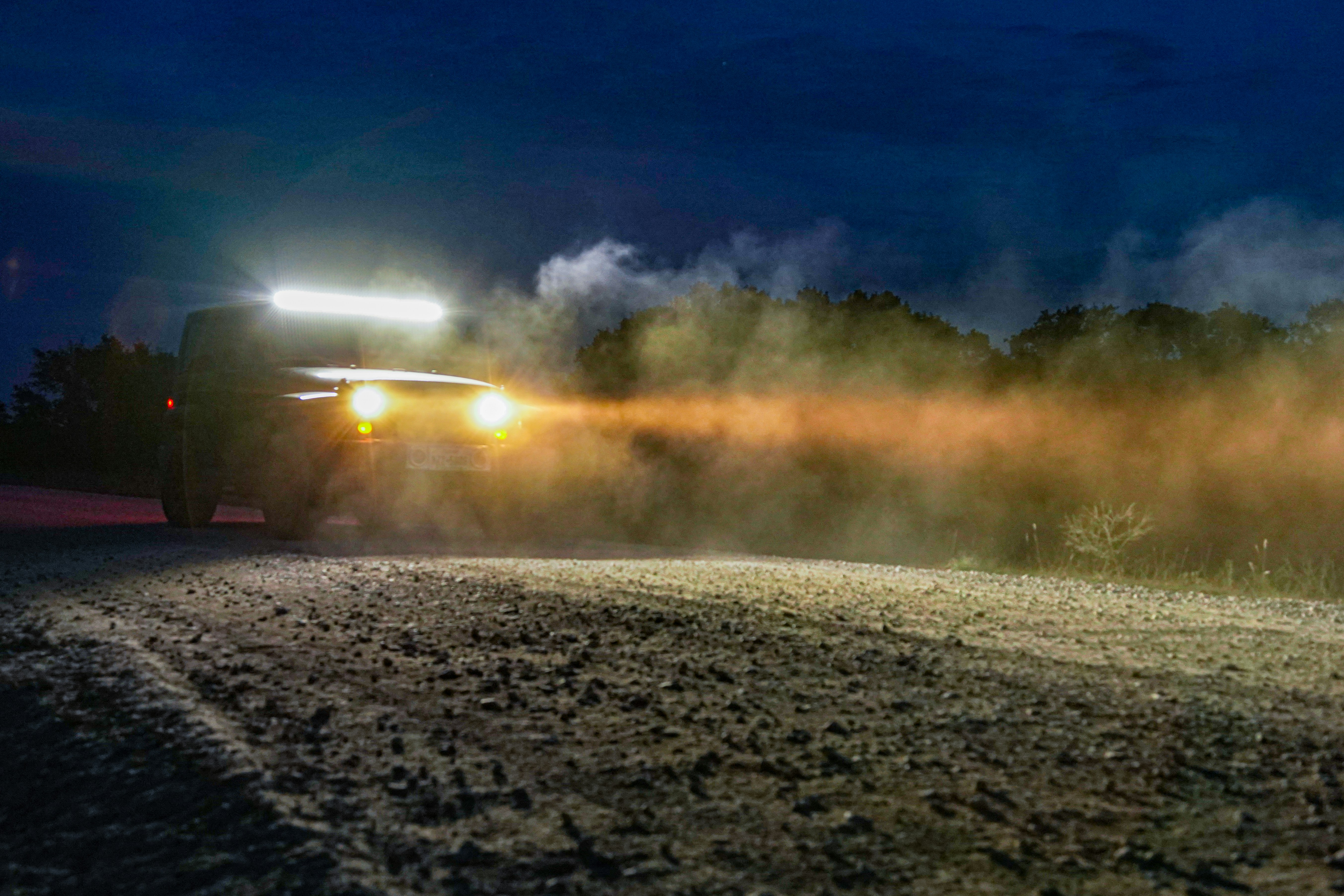 A truck driving down a dirt road at night photo – Free Jeep Image on ...