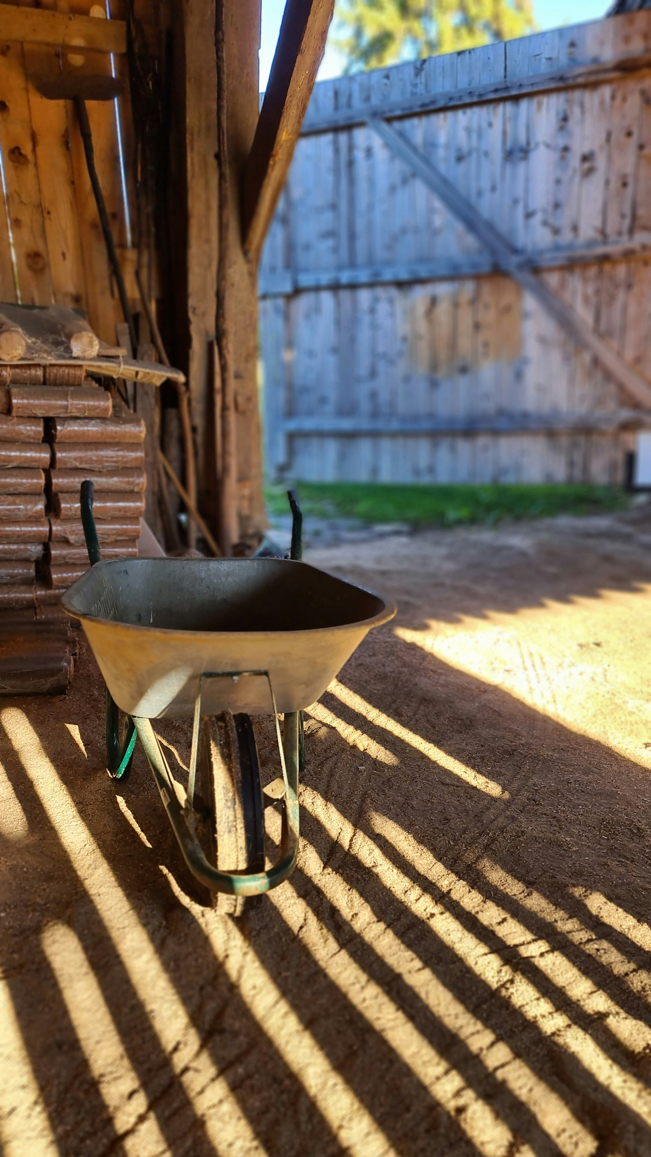 Wheelbarrow in a barn | a wheelbarrow sitting in the shade of a building