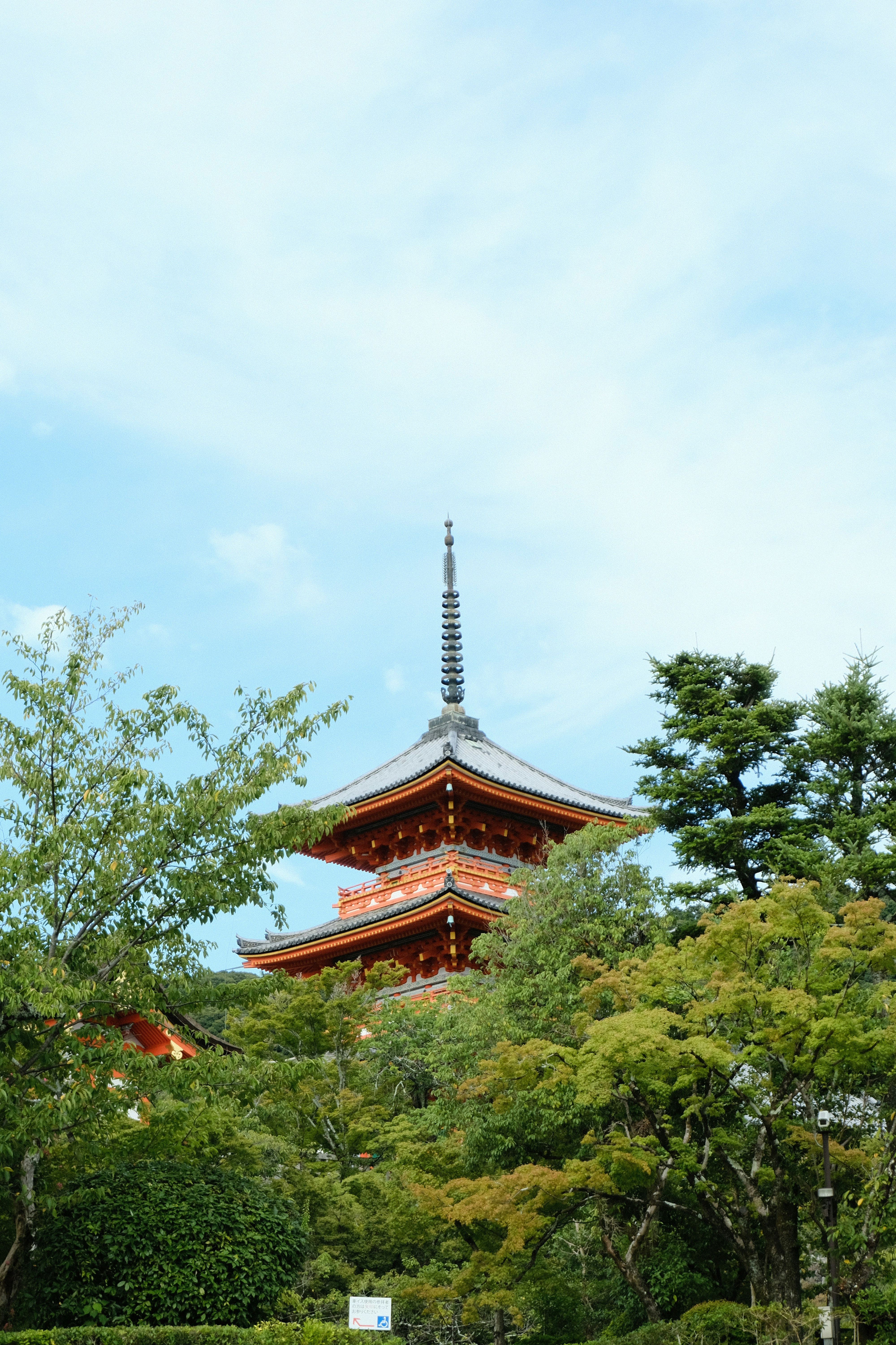A traditional pagoda peeks through lush greenery under a clear sky, showcasing the serene blend of architecture and nature.