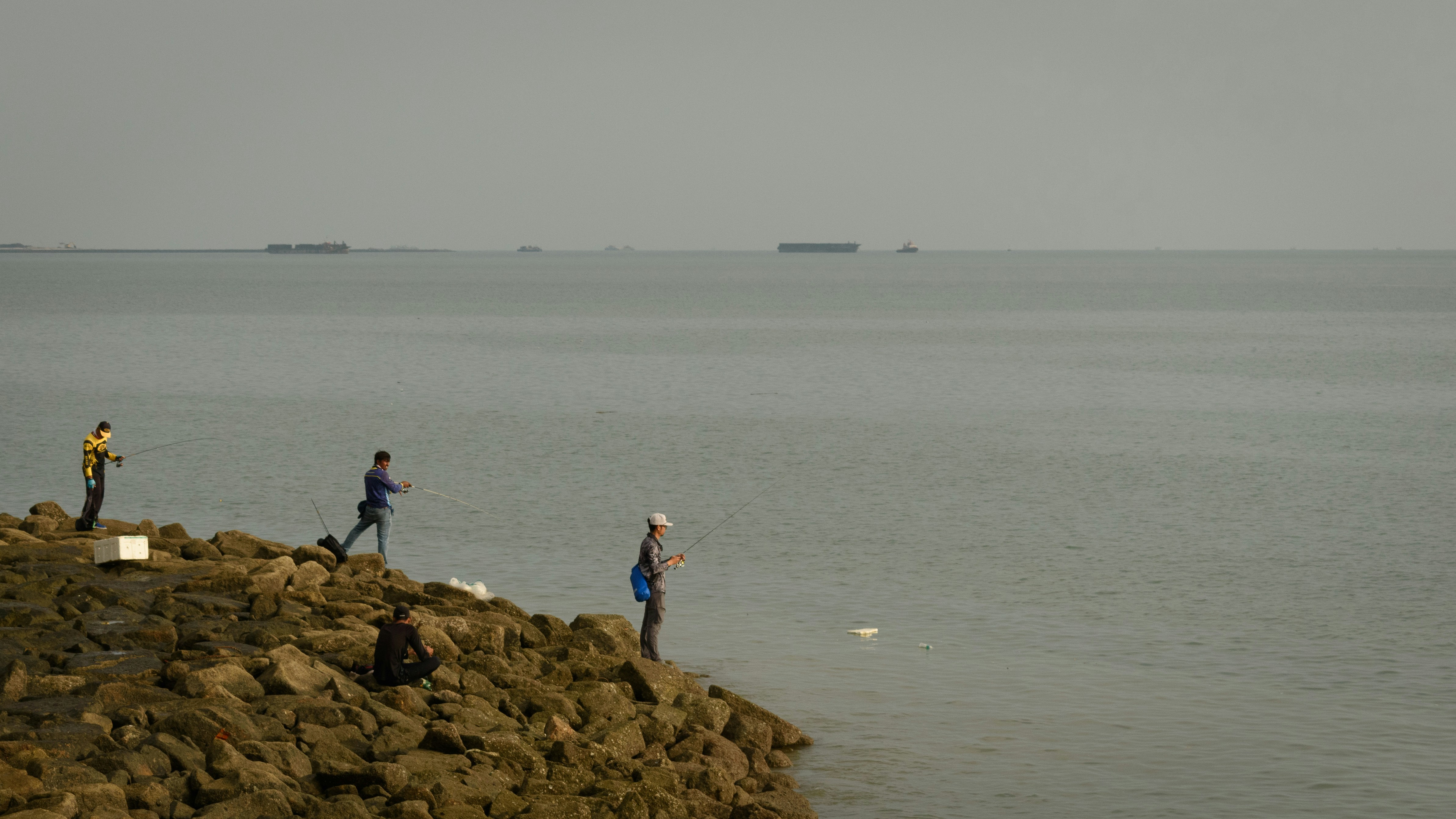 Three Anglers on a Rugged Breakwater Against a Quiet Sea