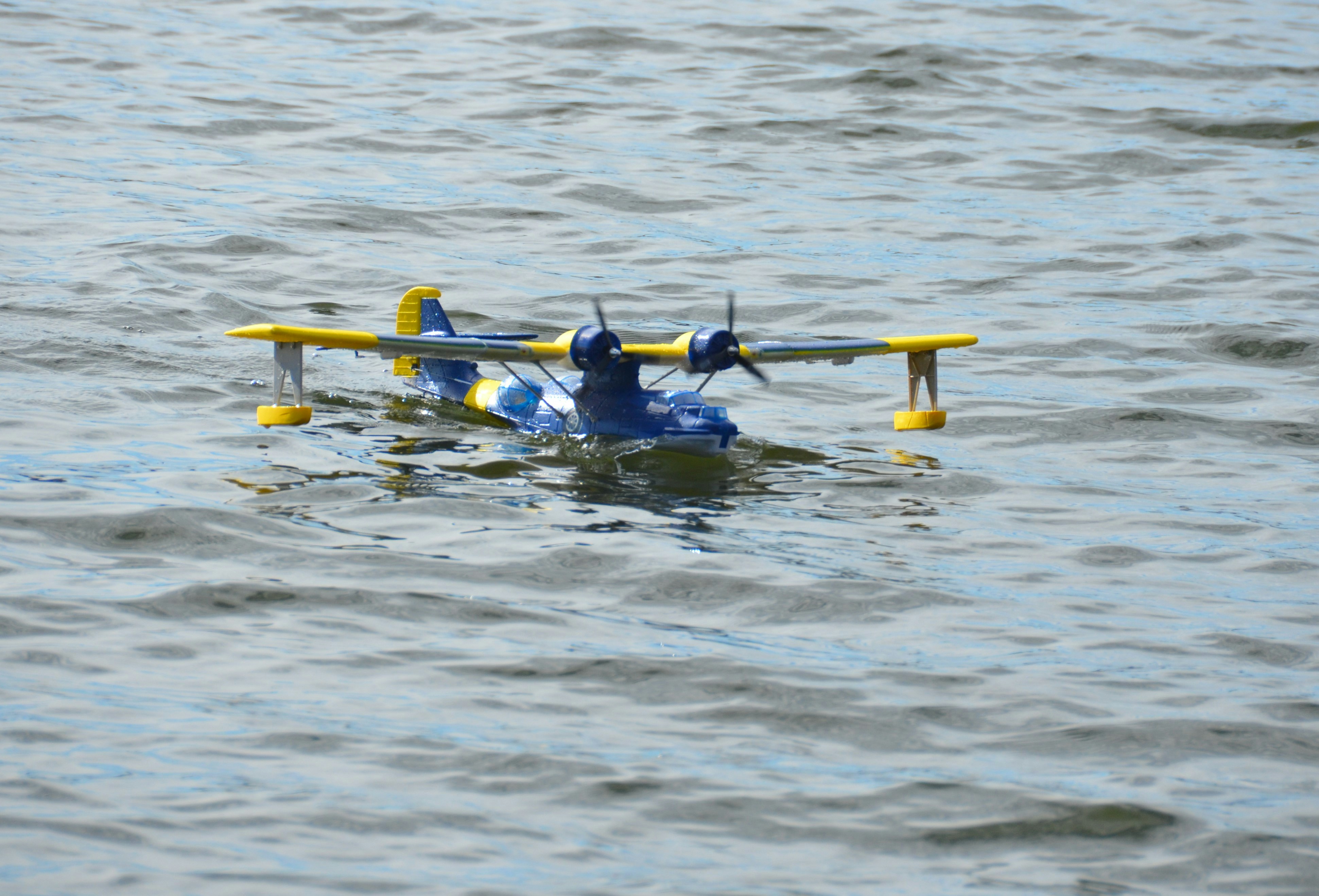 A blue and yellow plane floating on top of a body of water photo – Free ...