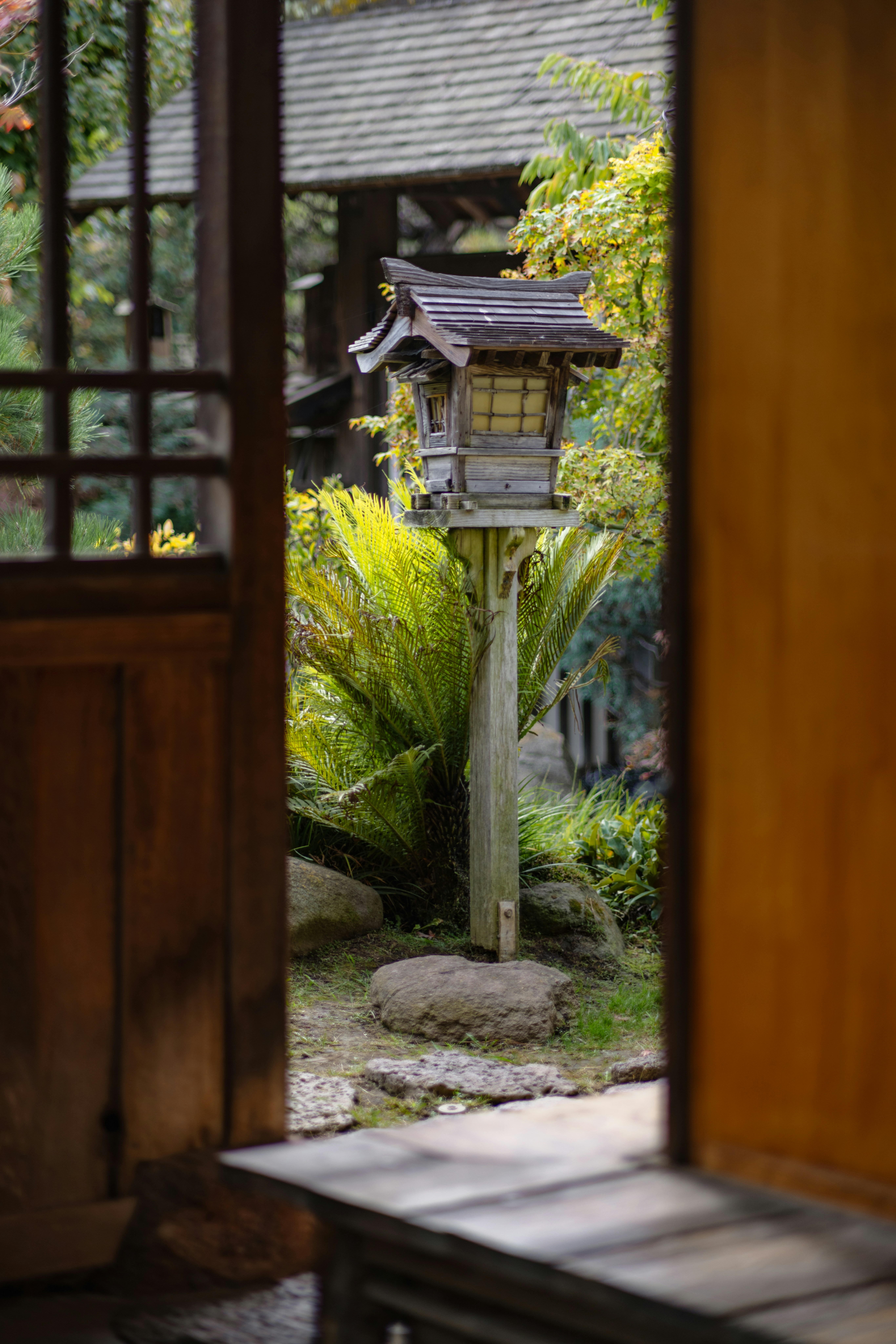 Stone Lantern Framed by a Wooden Portal in a Tranquil Japanese Courtyard
