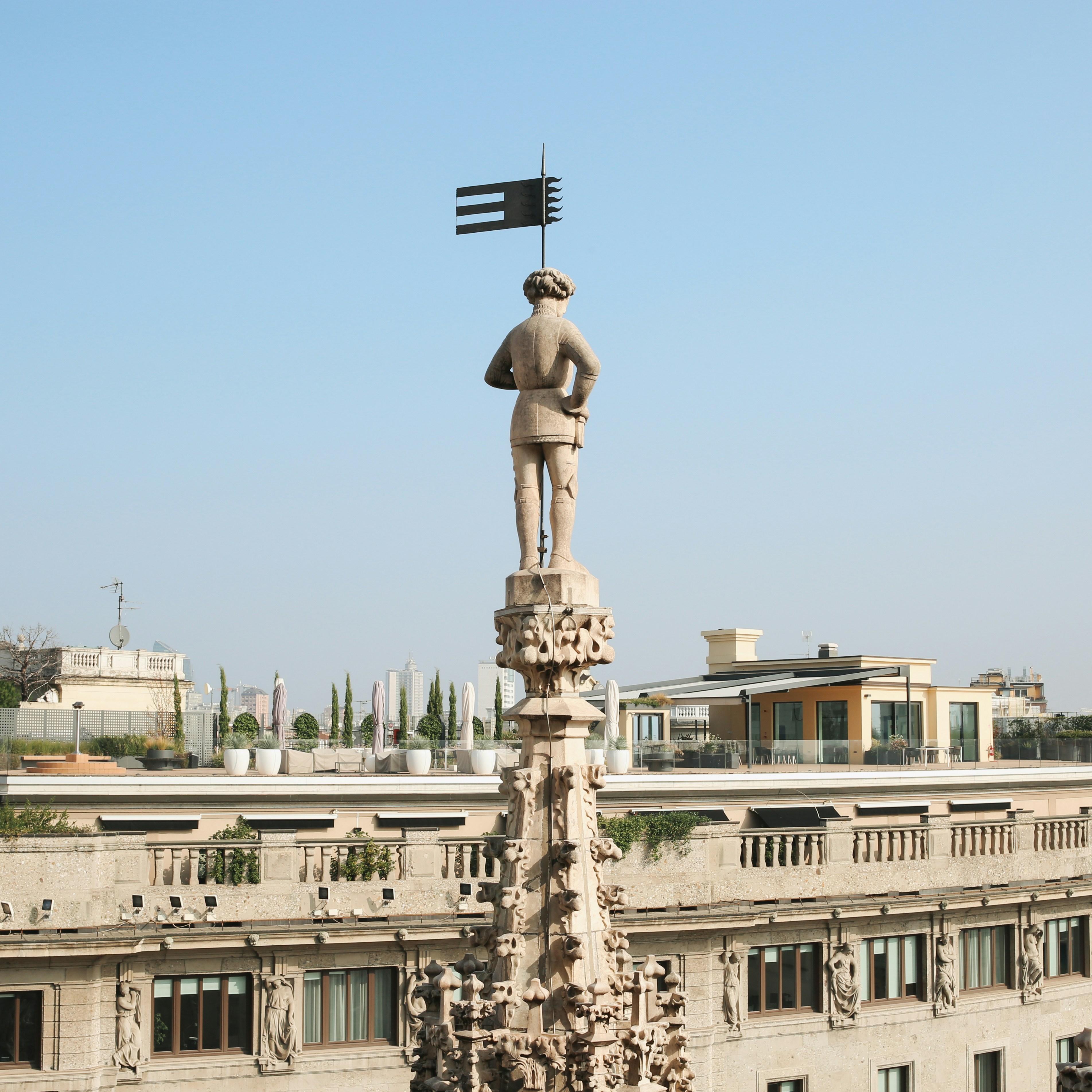 Stone Sentinel on a Rooftop Spire Over a Quiet Cityscape