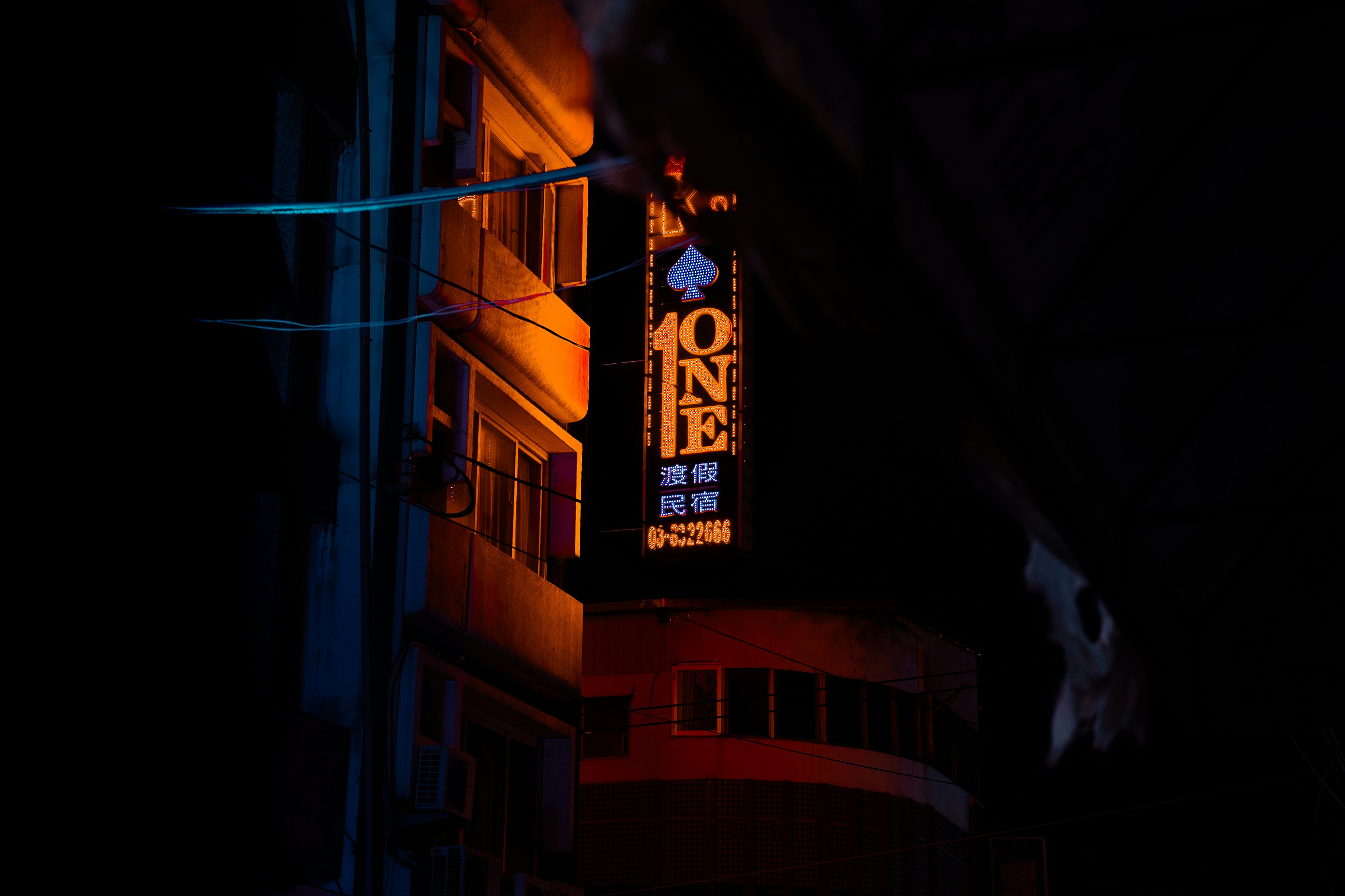 Illuminated neon sign for a venue, casting vibrant colors against the surrounding architecture at night.