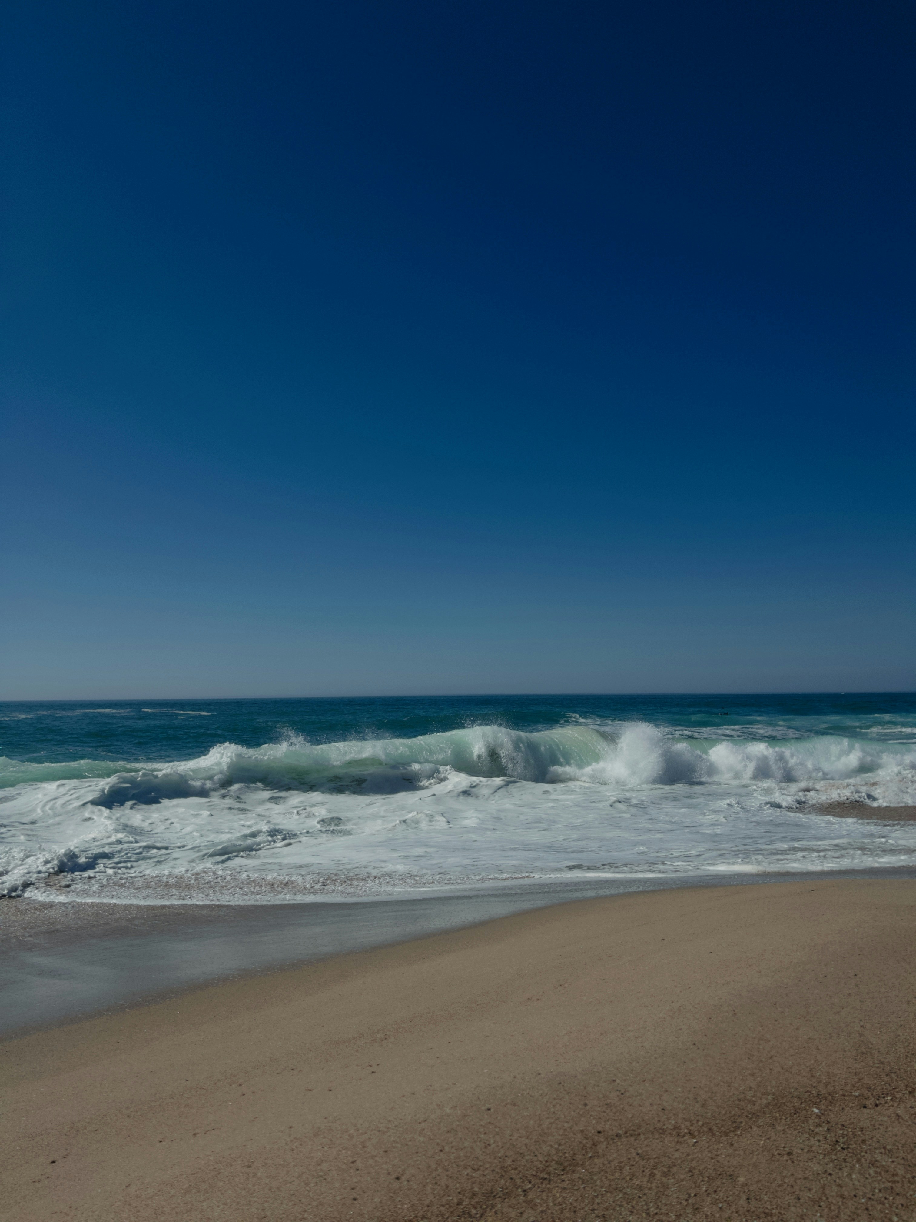 Une plage de sable avec des vagues qui entrent et sortent de l’eau ...