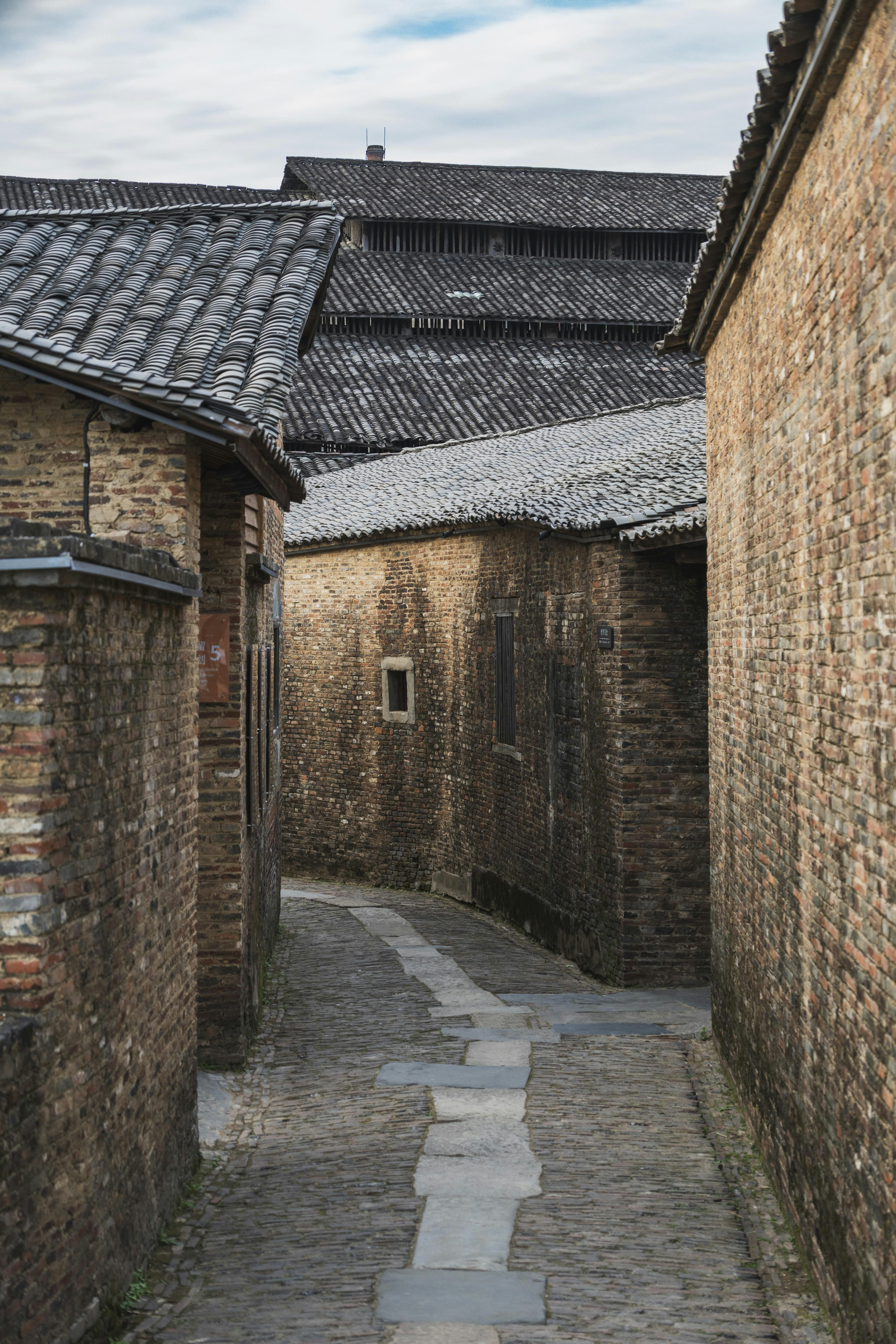 Between Brick Corridors: A Narrow Alley Reaching Toward Sloped Rooflines