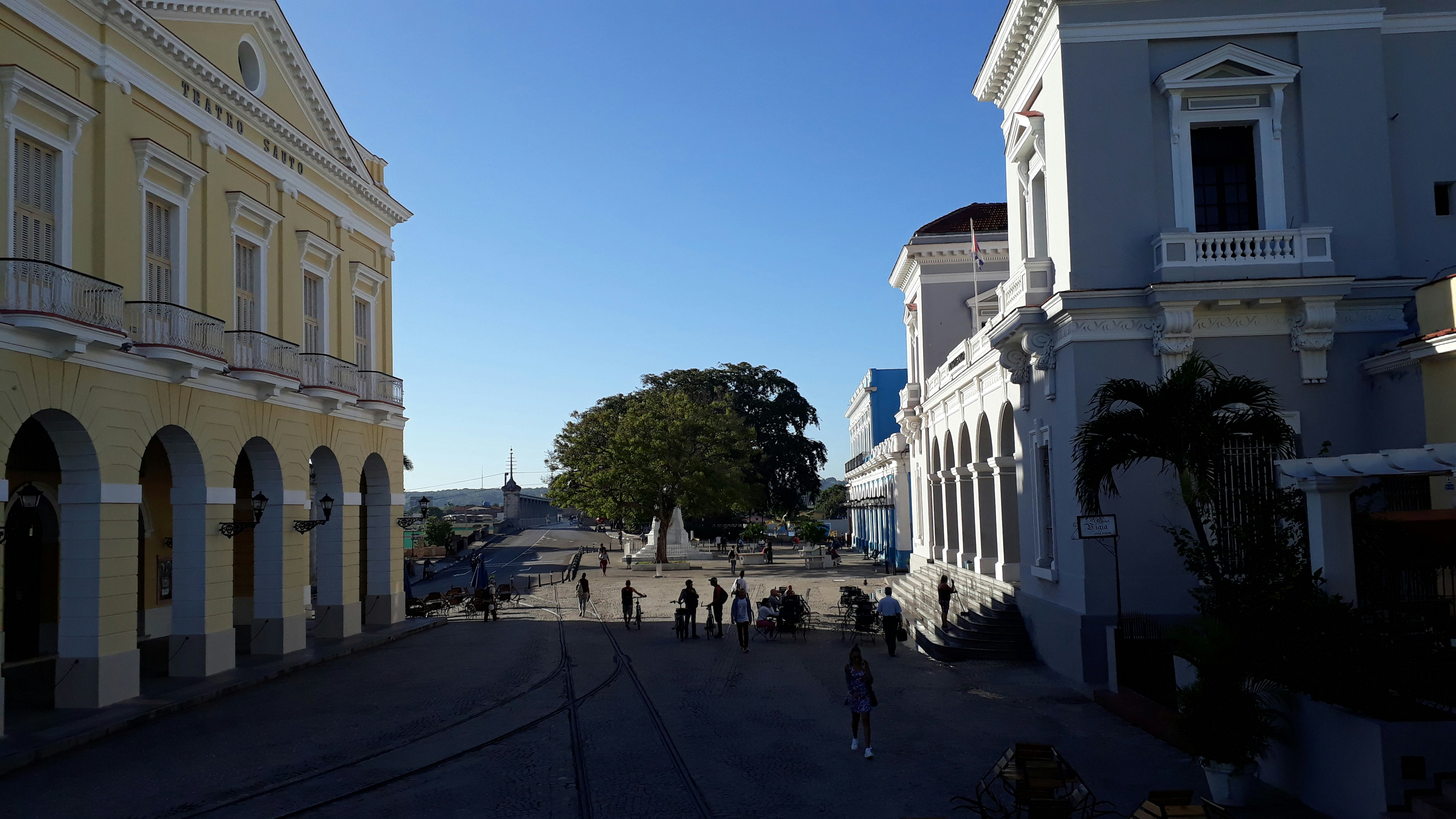 Plaza Vigía Ciudad de Matanzas | a group of people walking down a street next to tall buildings