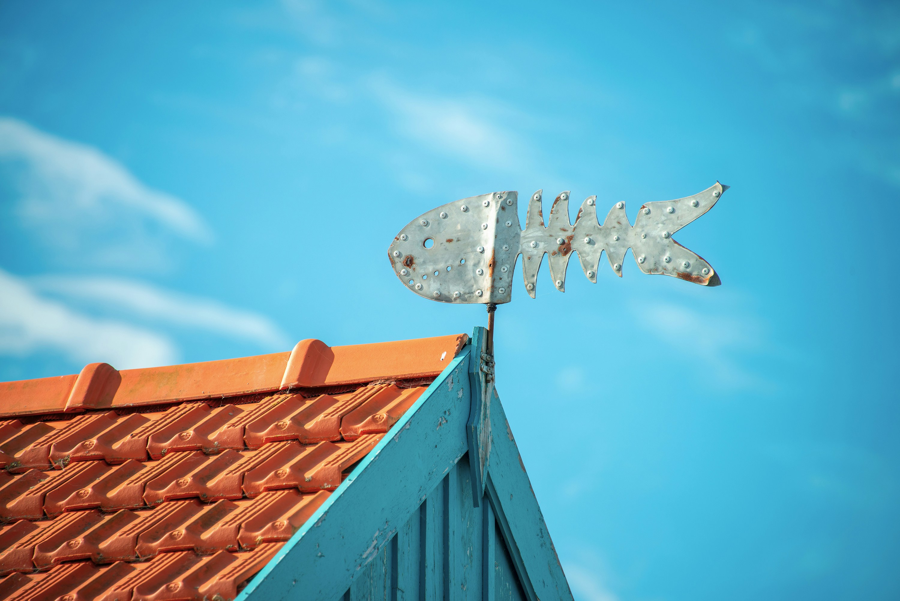 Turquoise Gable with a Weathered Fish Weathervane under a Clear Blue Sky