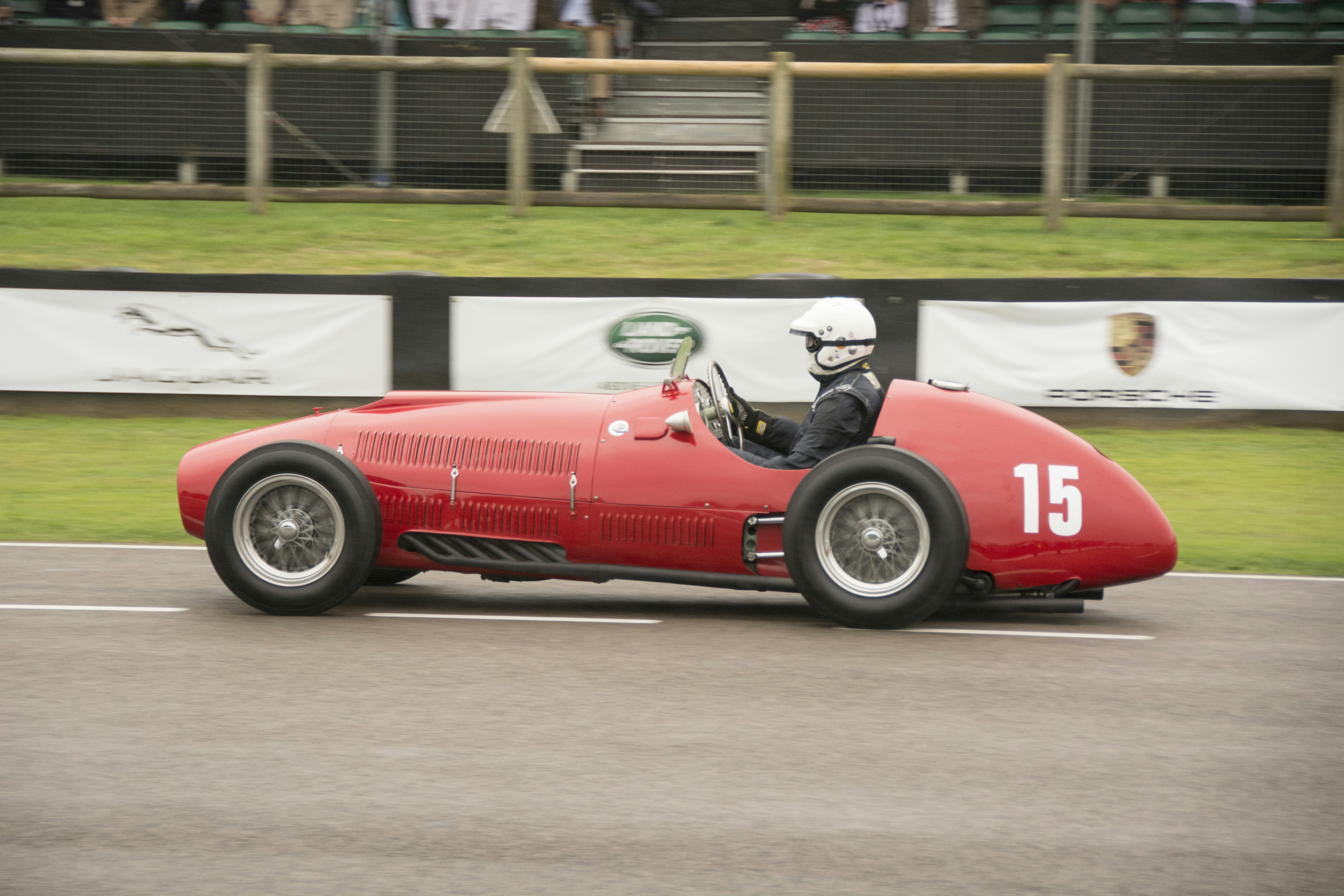 A man driving a red race car down a race track photo – Free Goodwood ...