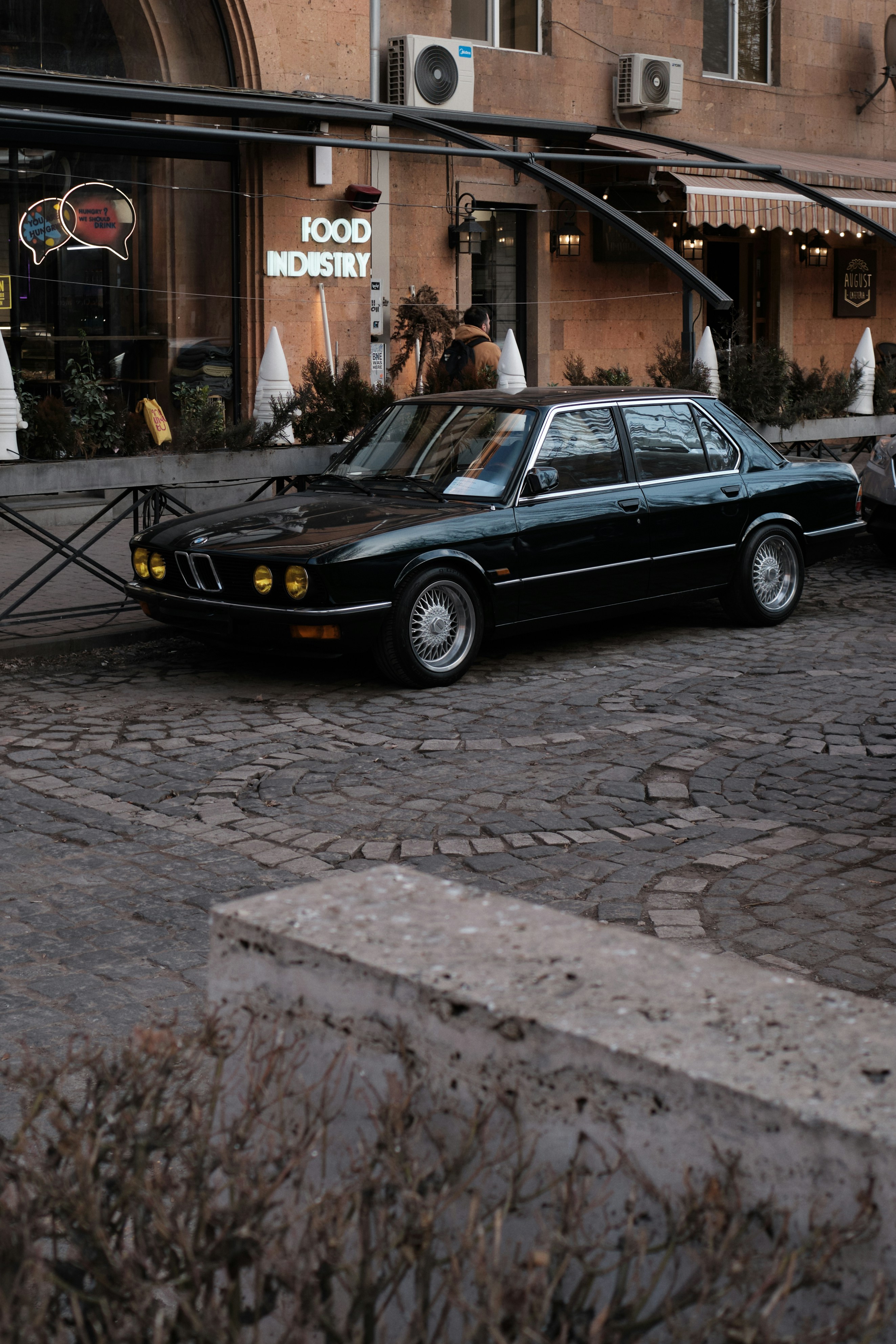 Midnight BMW E28 Pauses by a Cobblestone Café