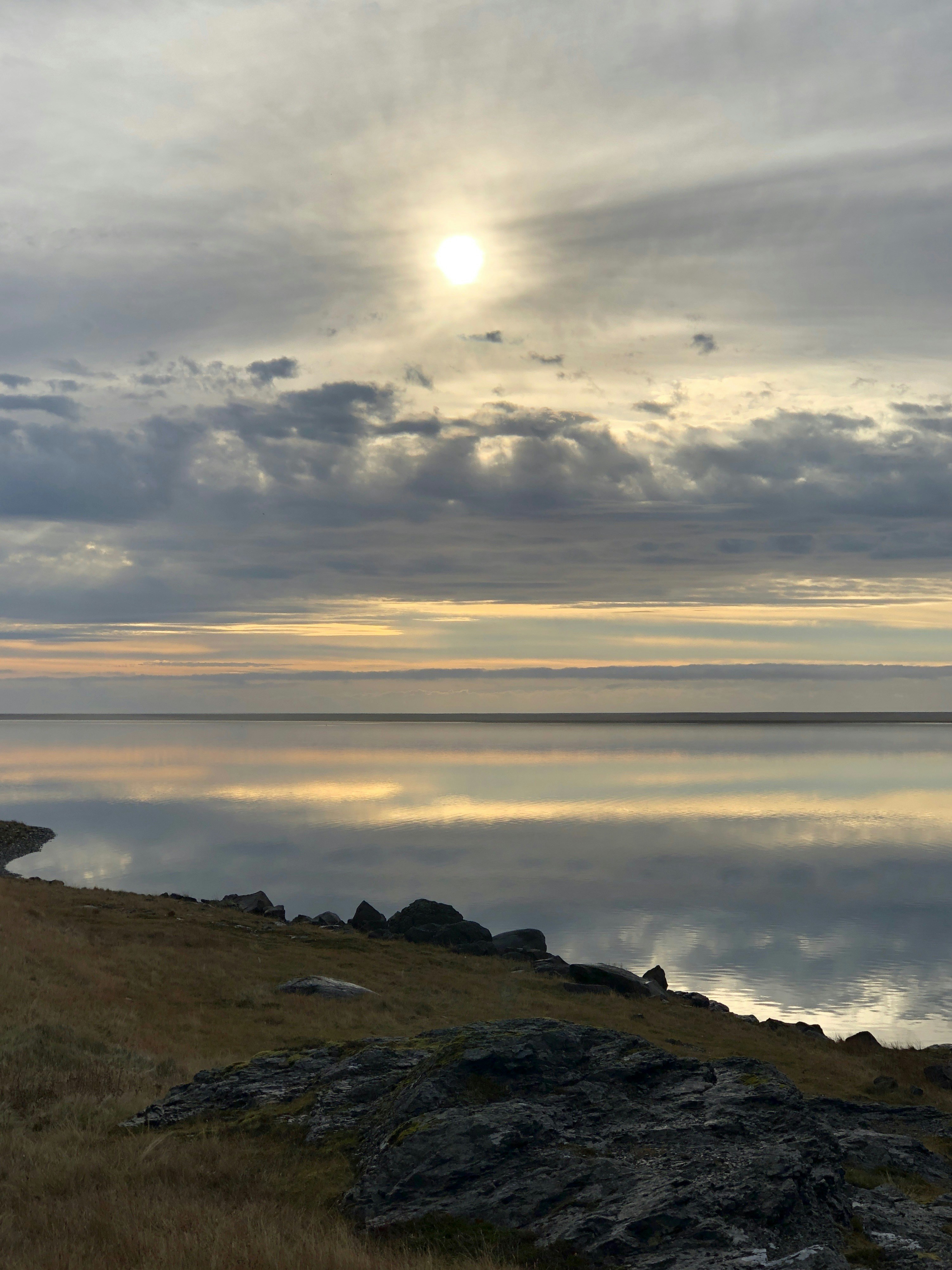 Dawn at the Edge of Quiet Water: Sun, Stone, and Soft Clouds