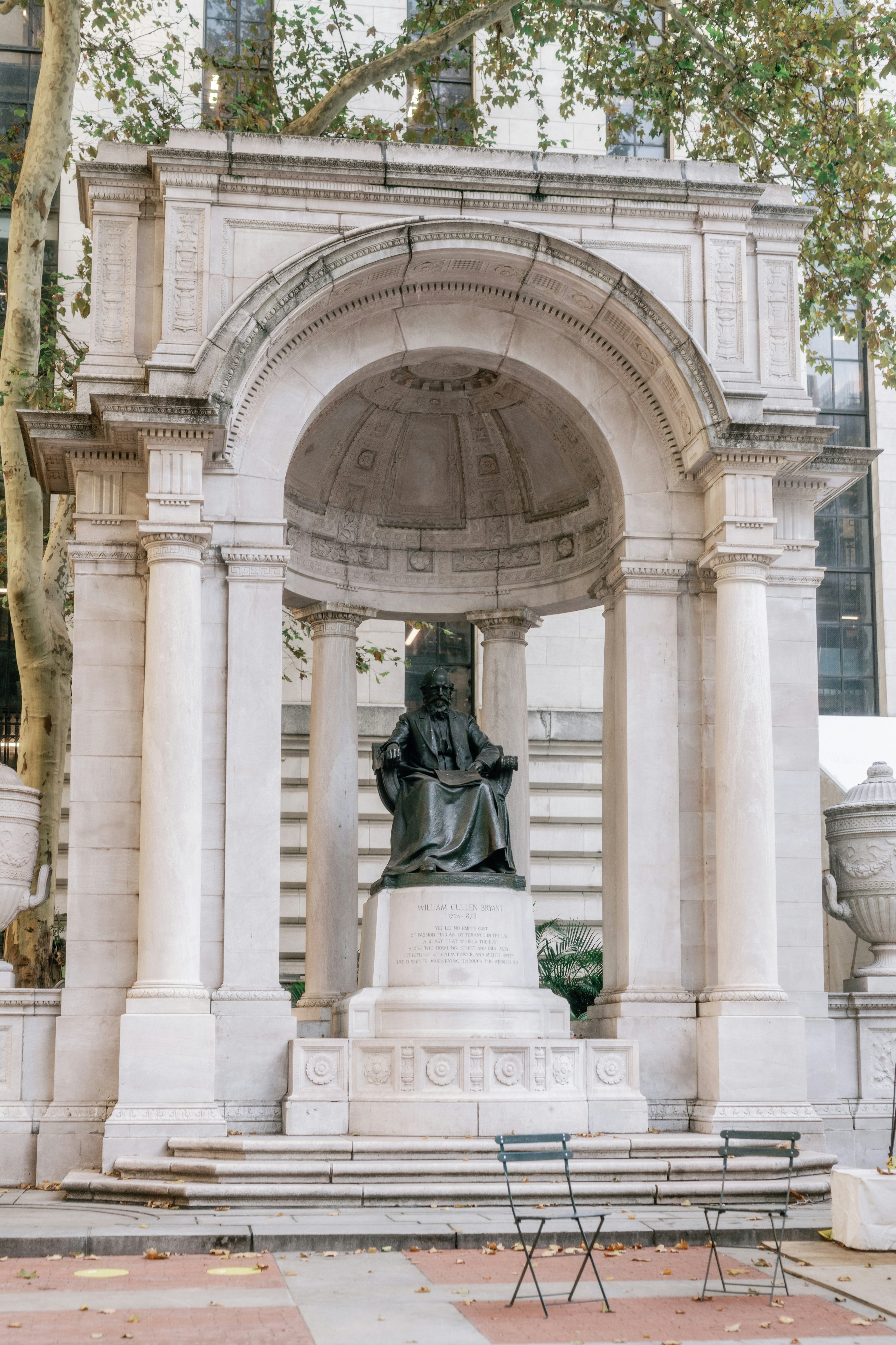 a statue of a man sitting on a bench in front of a building