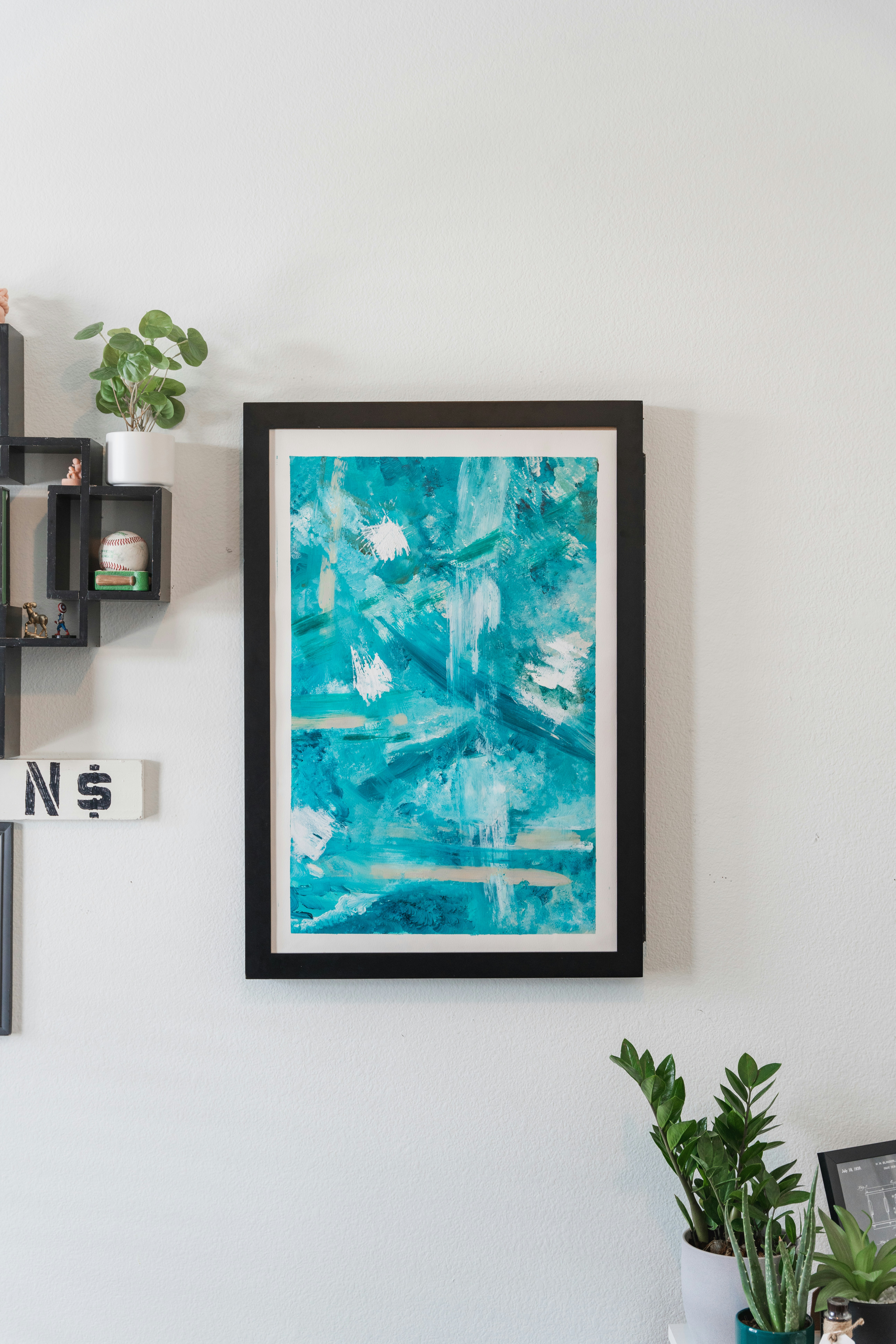 Foto Un cuadro colgado en una pared junto a una planta en maceta ...