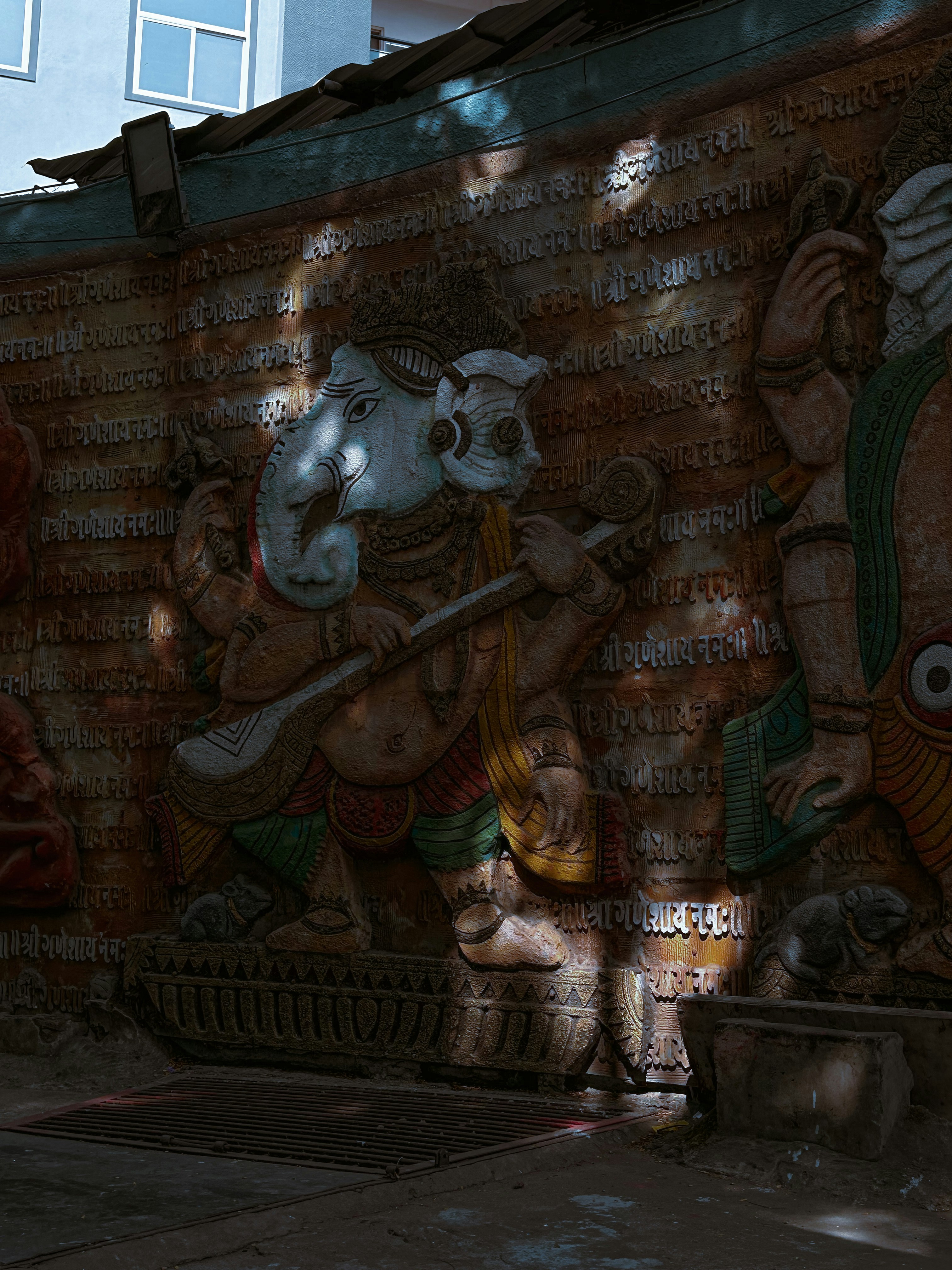 Intricate wall relief depicting a deity with an elephant head, surrounded by ancient inscriptions. The artwork showcases vibrant colors and detailed craftsmanship.